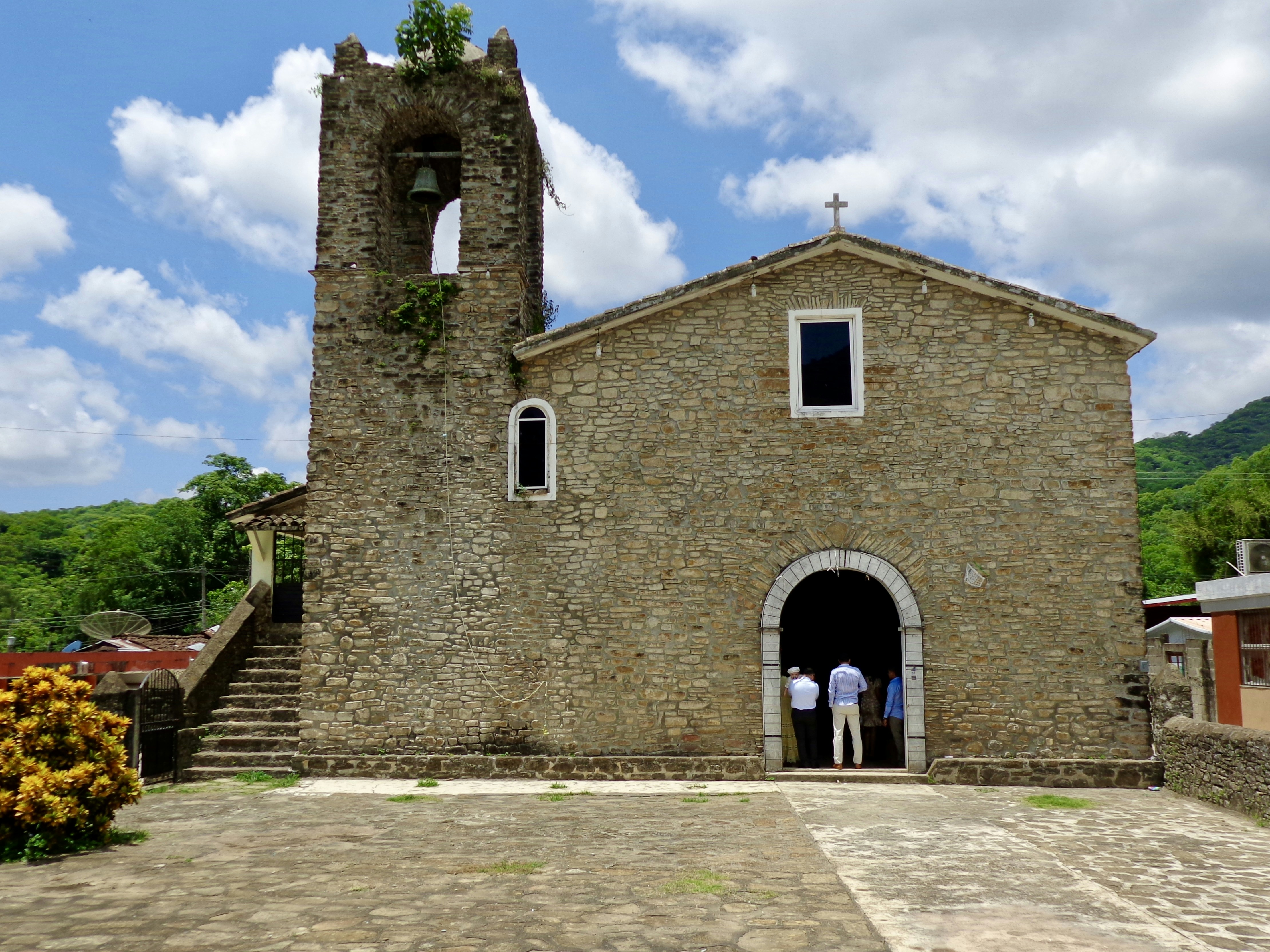 Stone church with arched doorway as courtyard hums with visitors