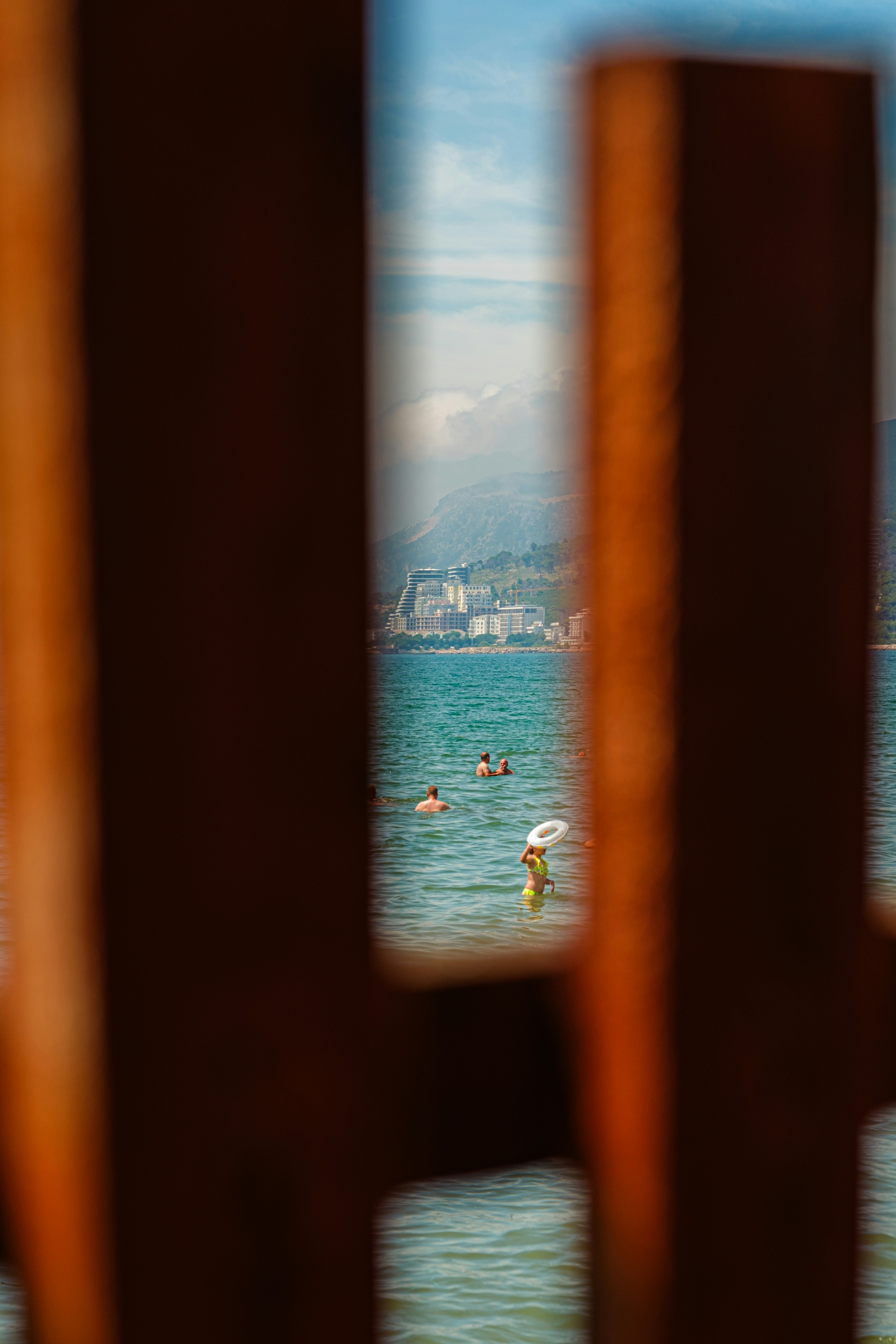 Through the Gaps: A Sea of Tops and Towers Framed by Wooden Slats