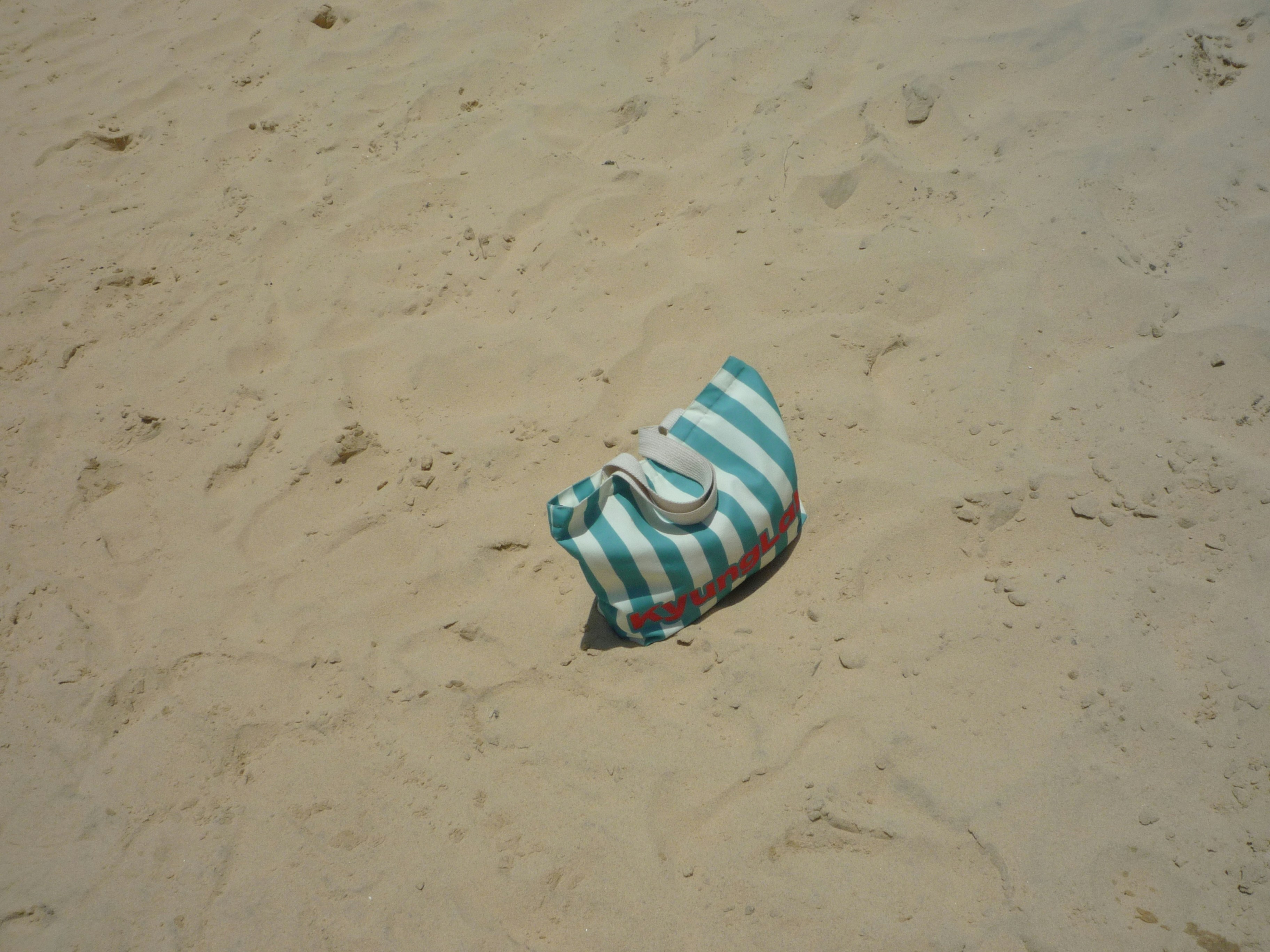 Stripes in the Sand: A Striped Tote Resting on Sunlit Beach