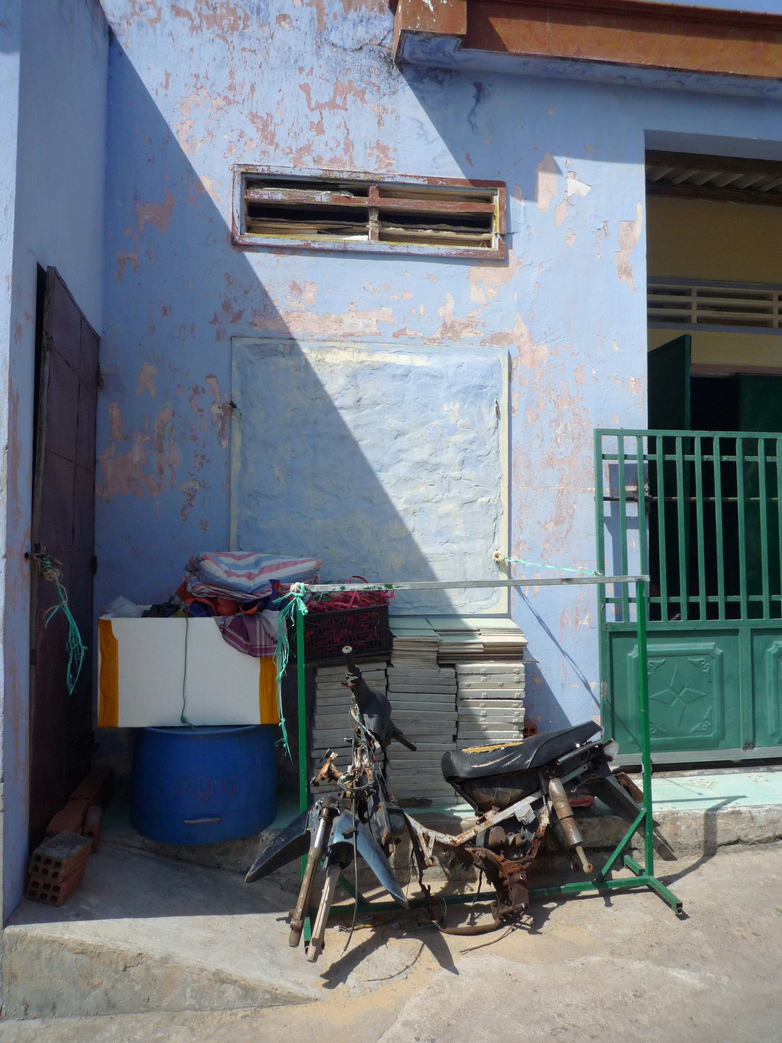 Blue Facade, Shadowed Doorway, and a Junked Motorcycle