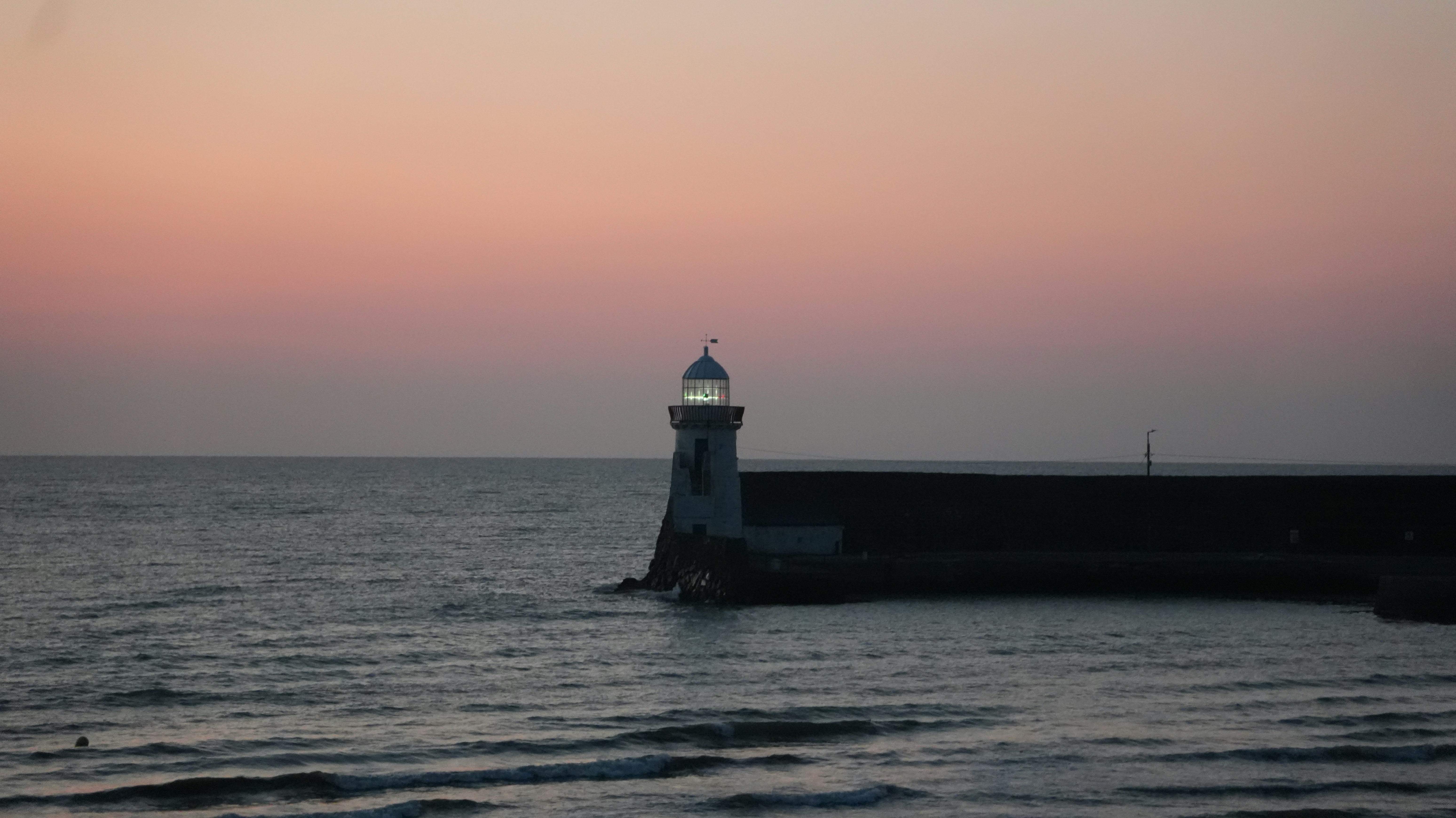 Lighthouse at Twilight: A Quiet Breakwater Embracing the Calm Sea