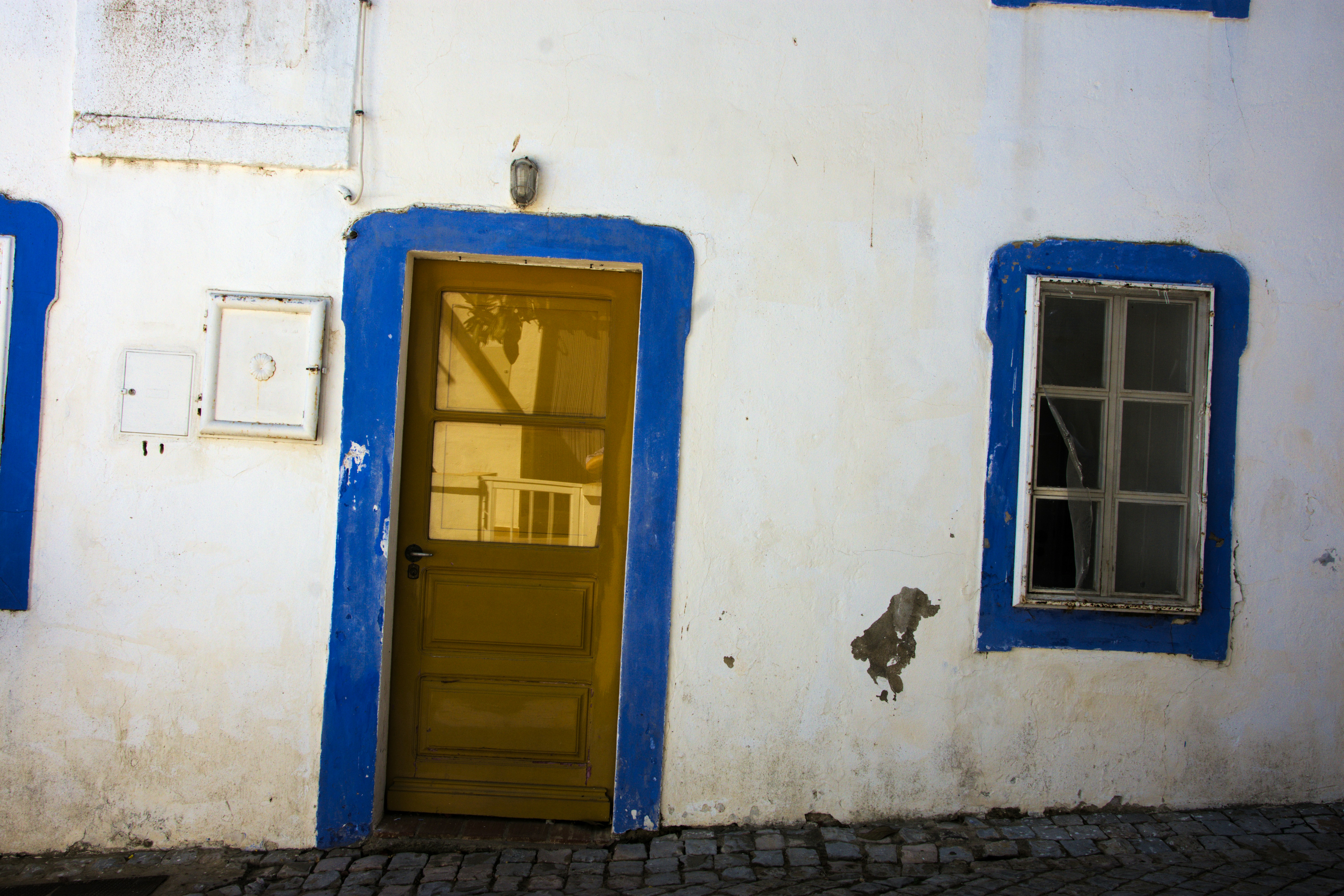 Blue-trimmed doorway in sunlit white wall