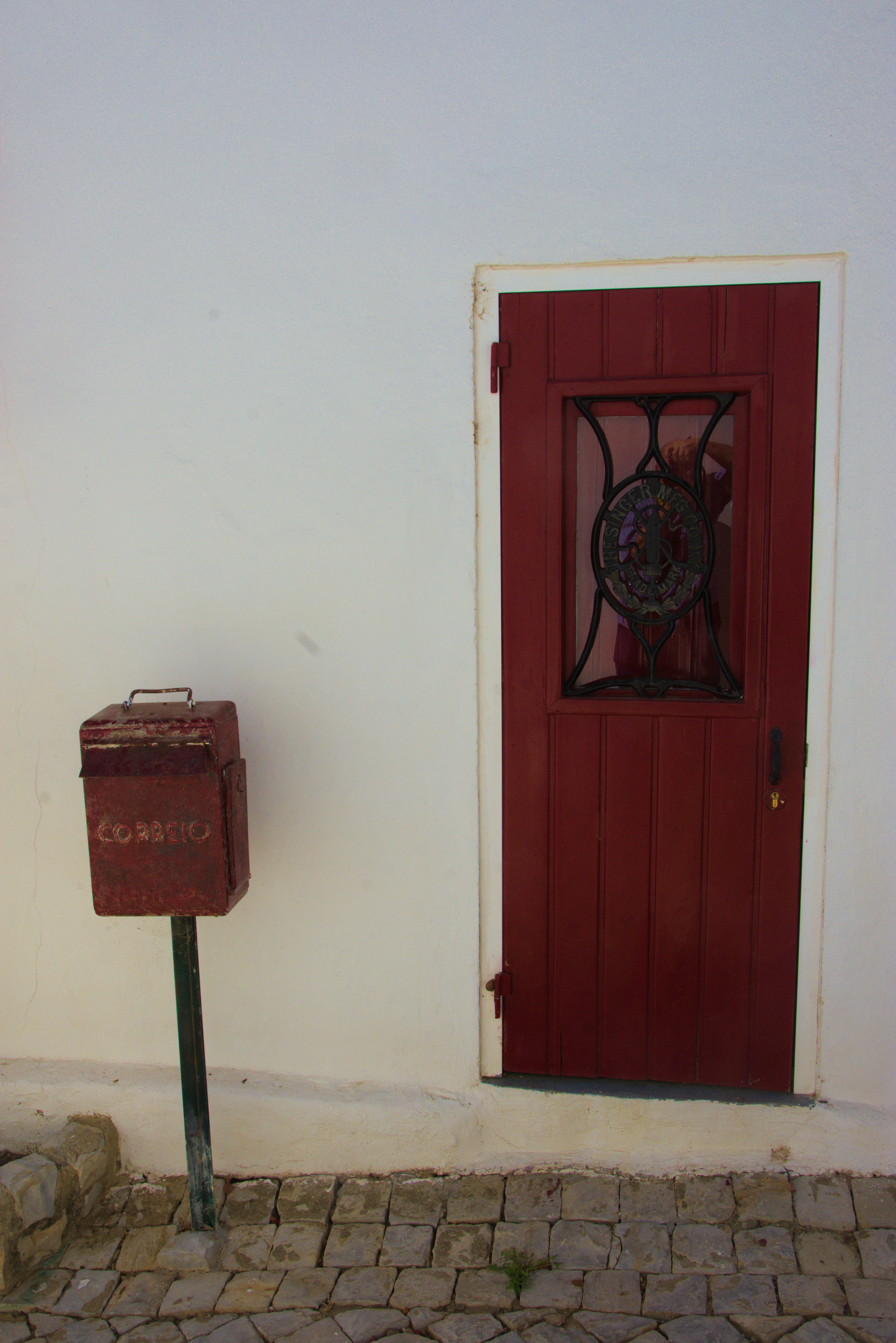 Red door and mailbox on a sunlit stucco wall