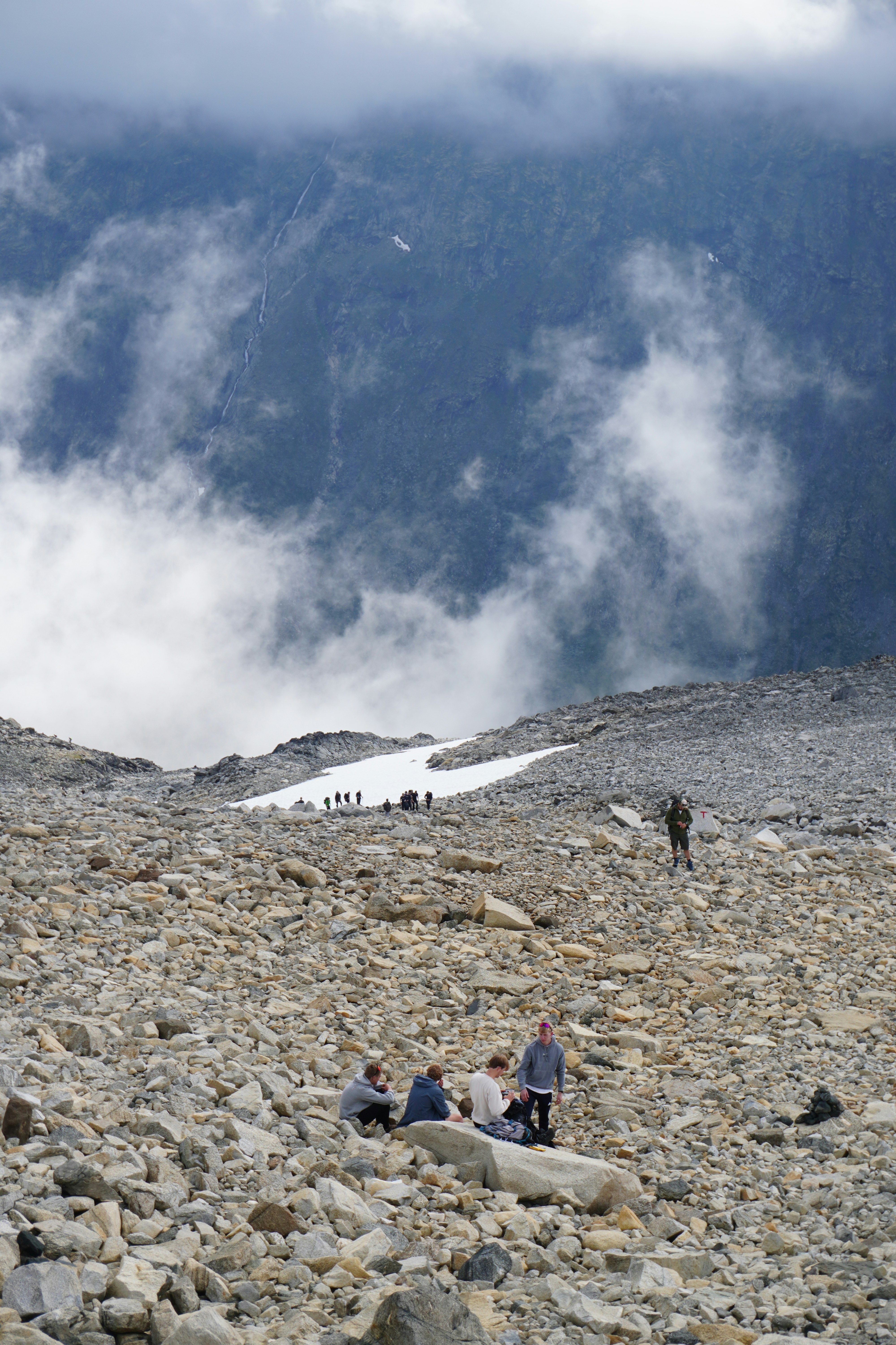 Climbers Resting on a Snow-dlecked Ridge Under a Vast, Cloud-Swept Sky