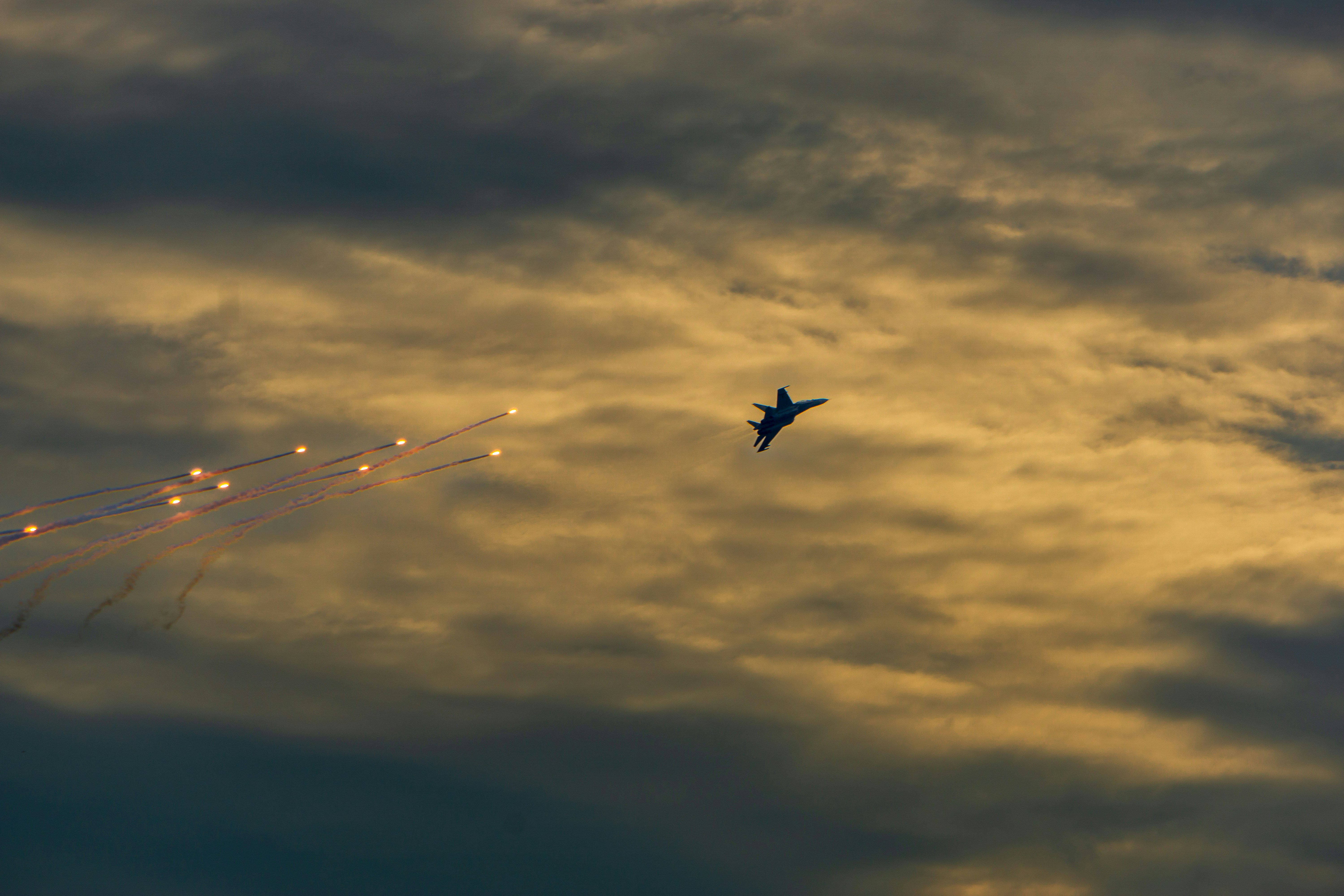 Nightflight: a lone jet breaks through golden high clouds