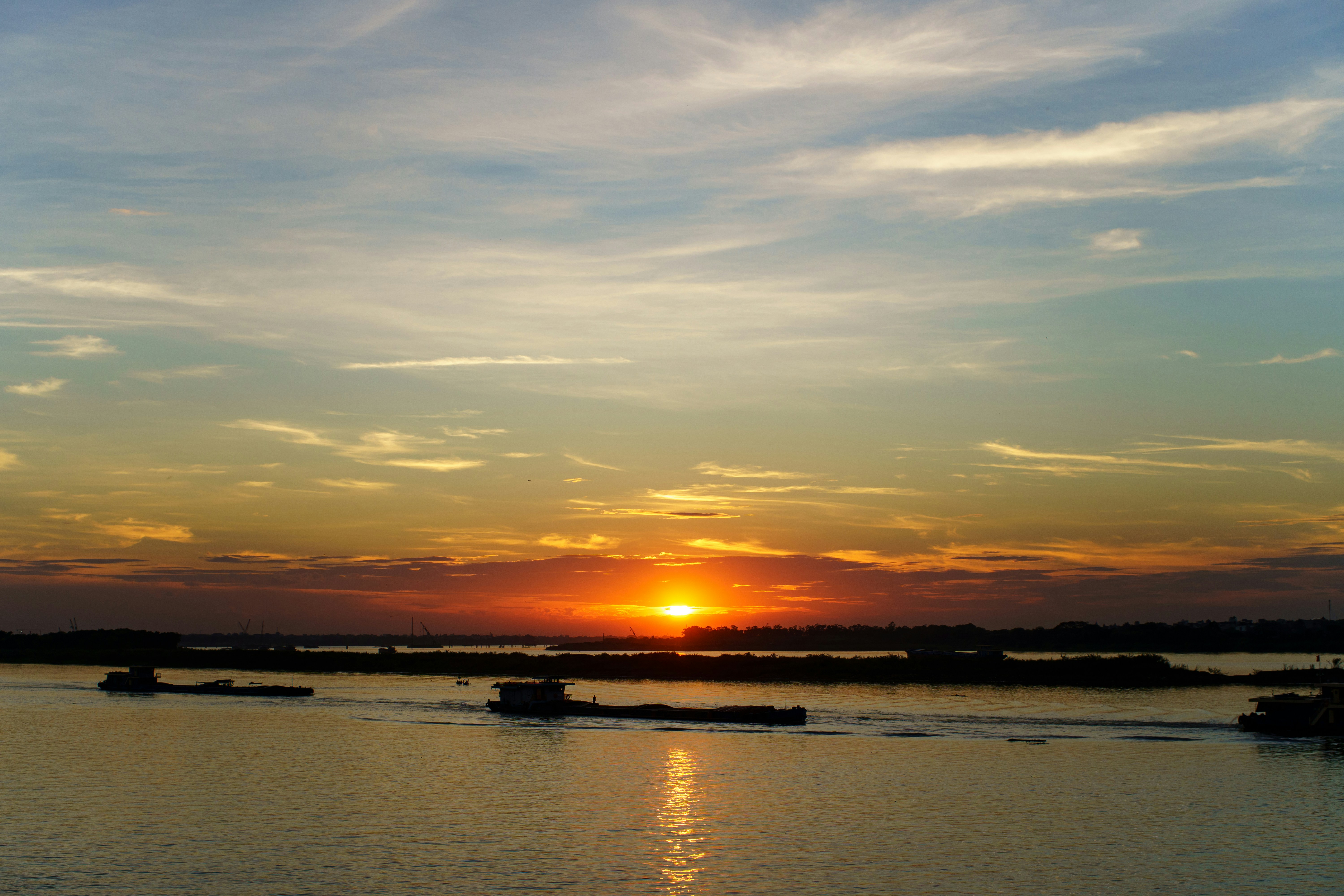 Sunlit Horizon: Boats Drift Along a Serene Seascape at Dusk