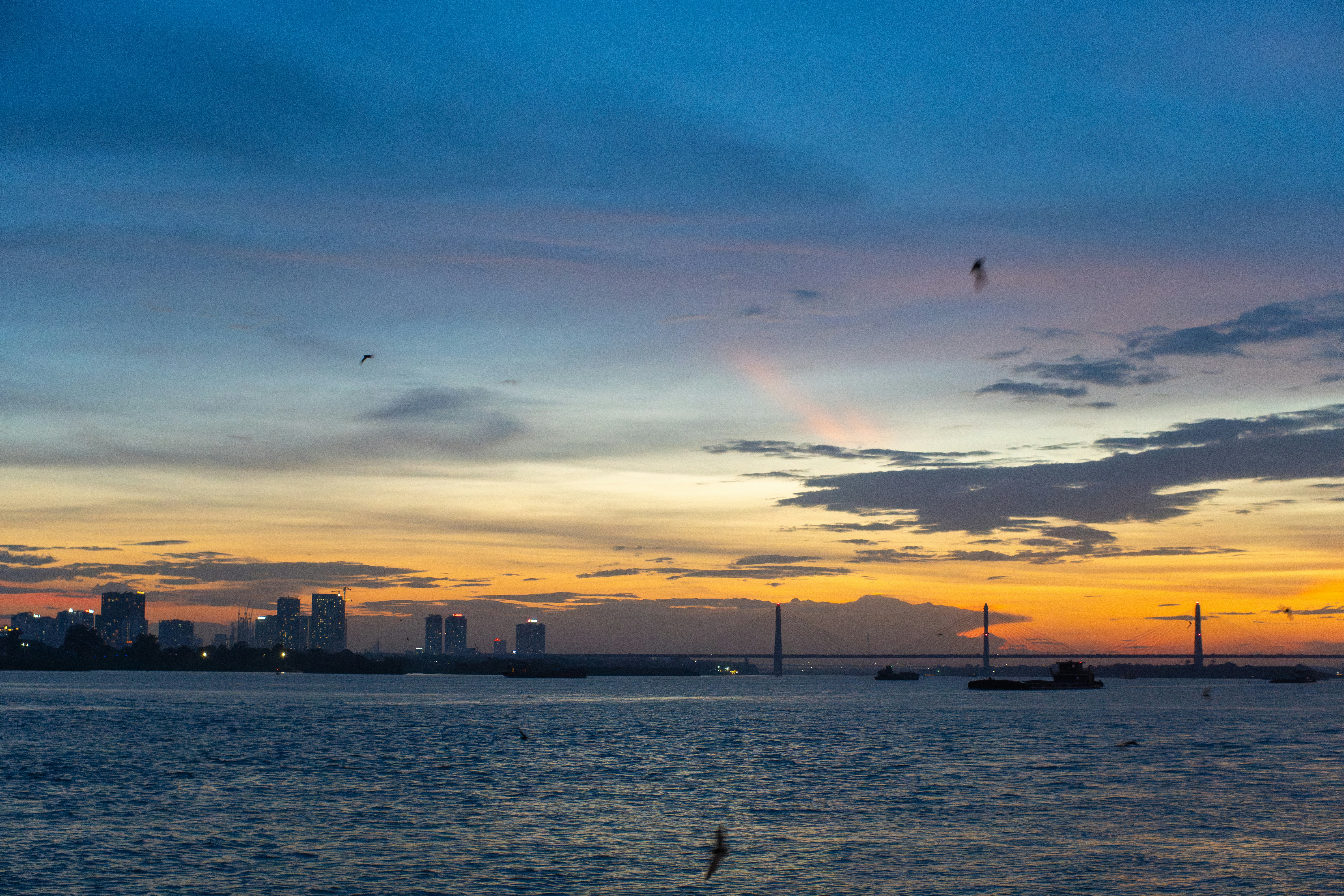 Sunset Over a Quiet Harbor with Distant City Silhouette
