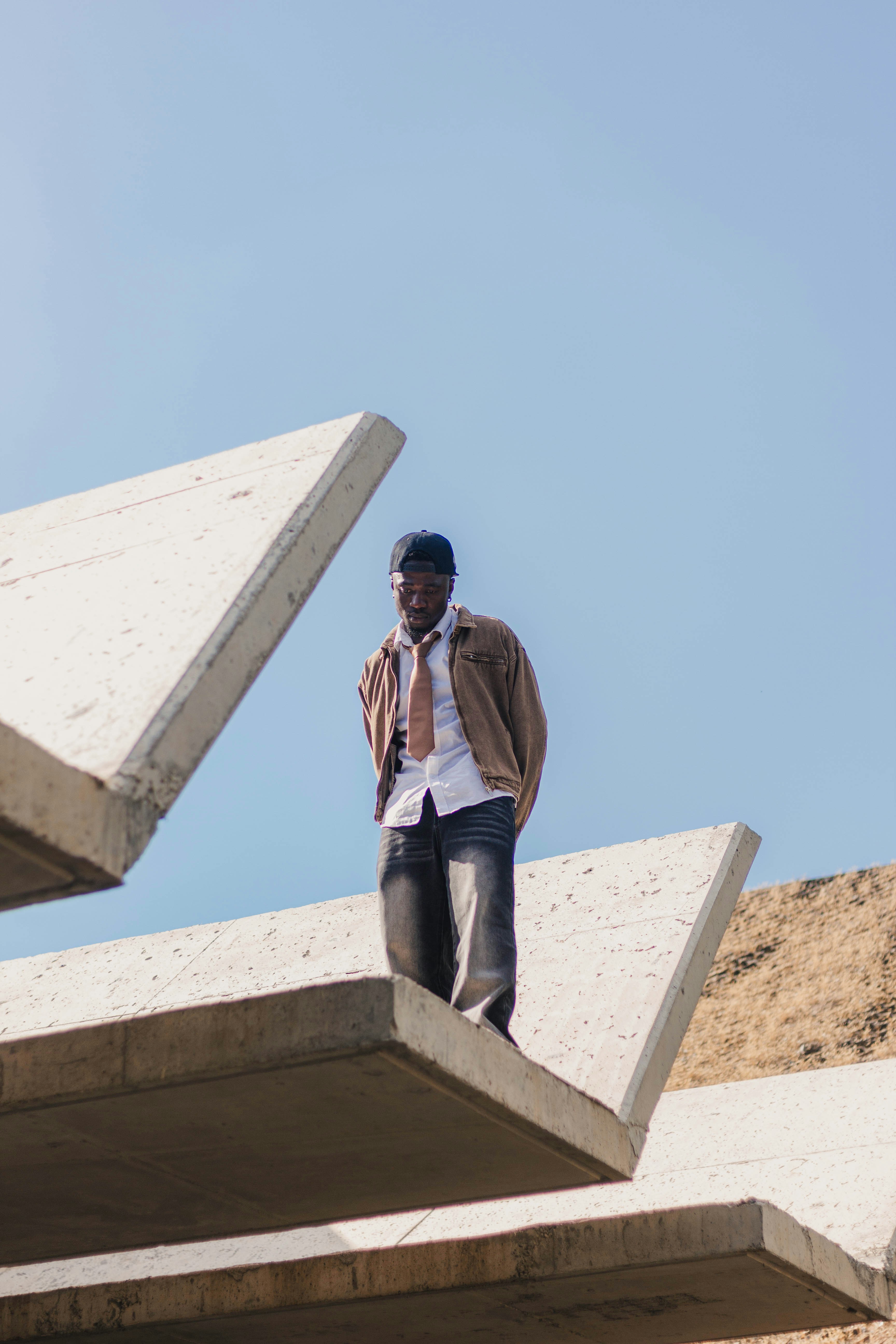 Architectural Edge: A lone figure on concrete shards beneath a clear blue sky