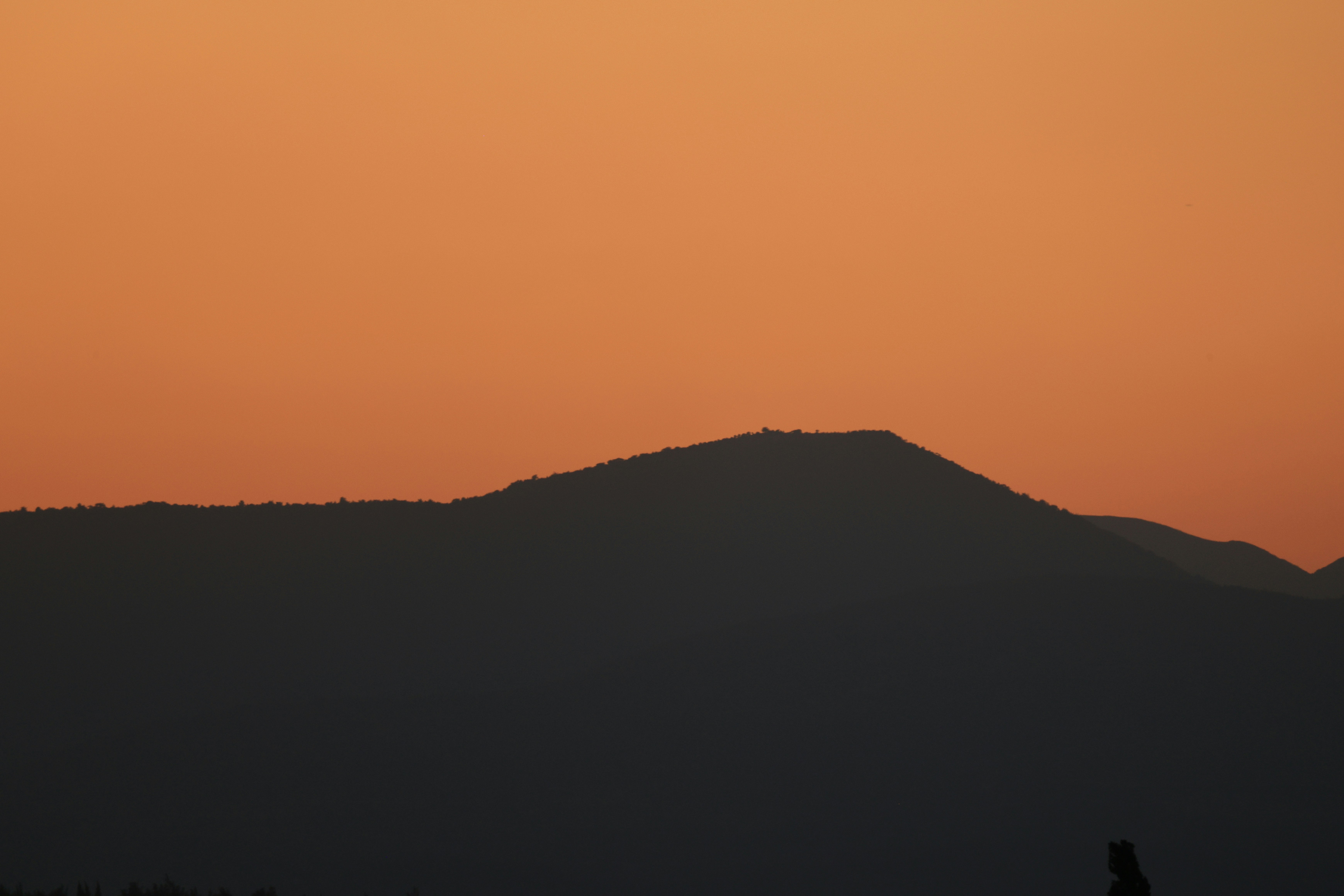 Silhouette at Dusk: A Quiet Mountain Crowned by Warm Sky