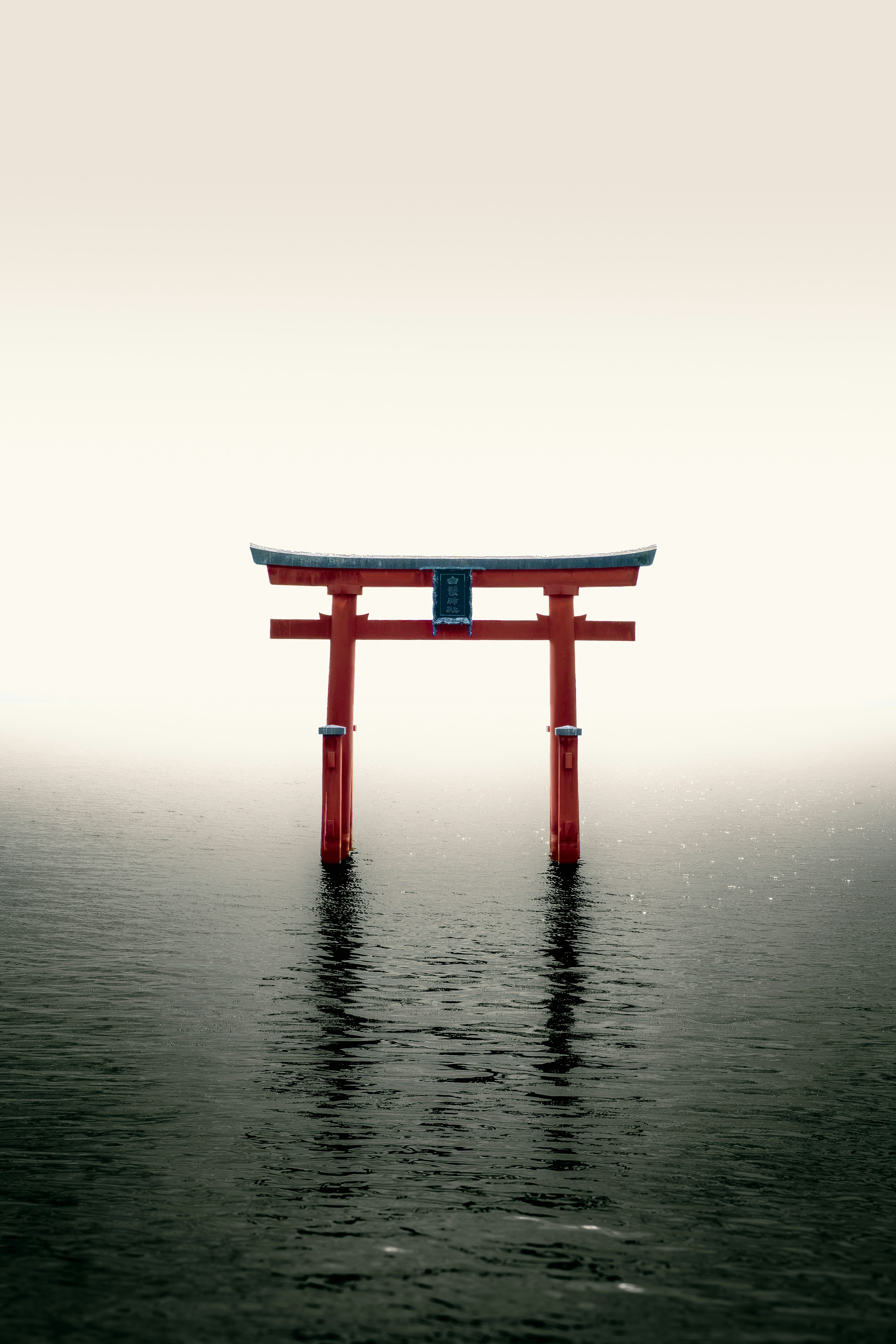 Red Torii Rising from Quiet Sea Under a Pale Horizon