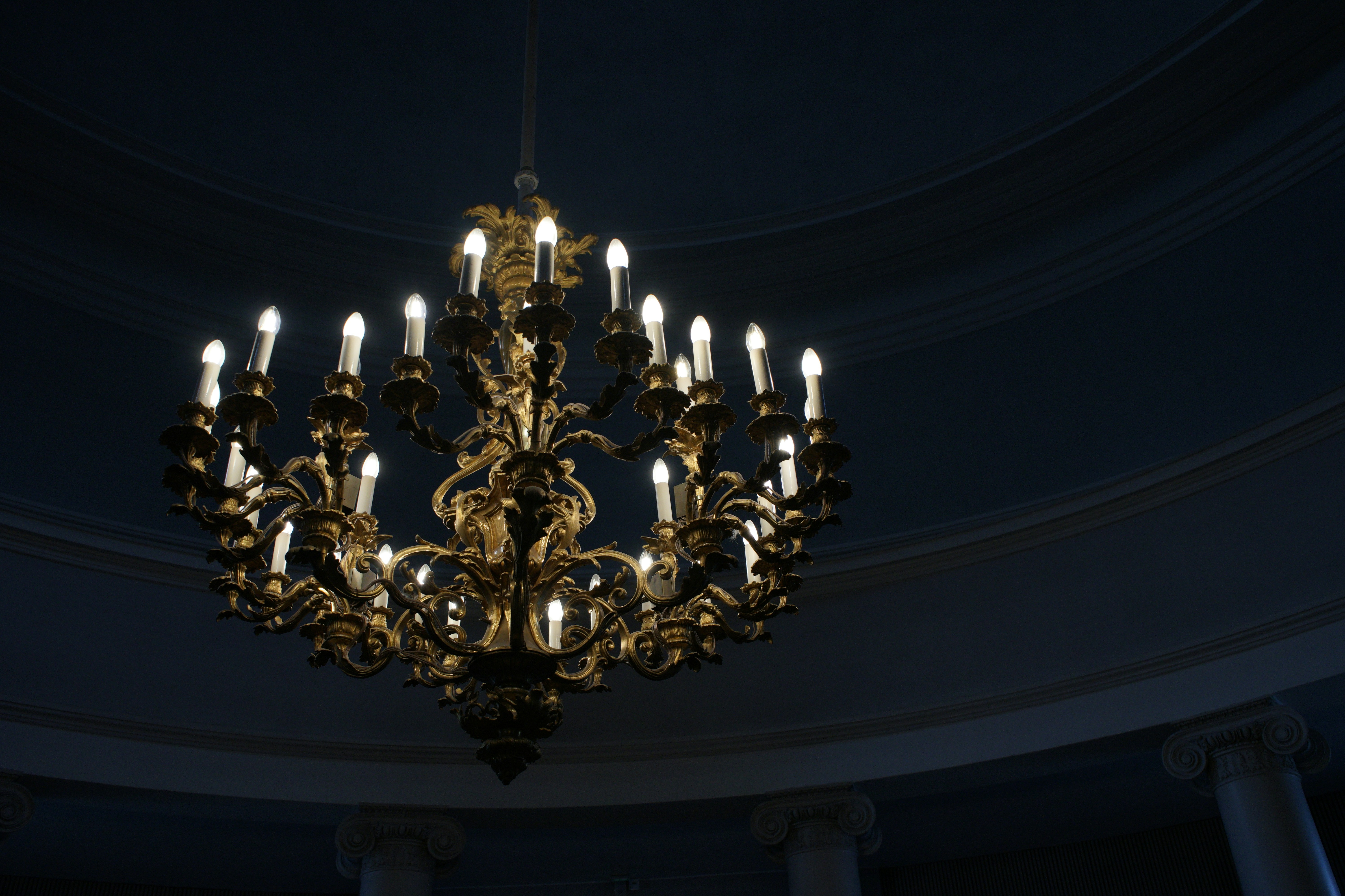 Gaslit Elegance: A Single Chandelier Casting Warm Shadows in a Dim Rotunda