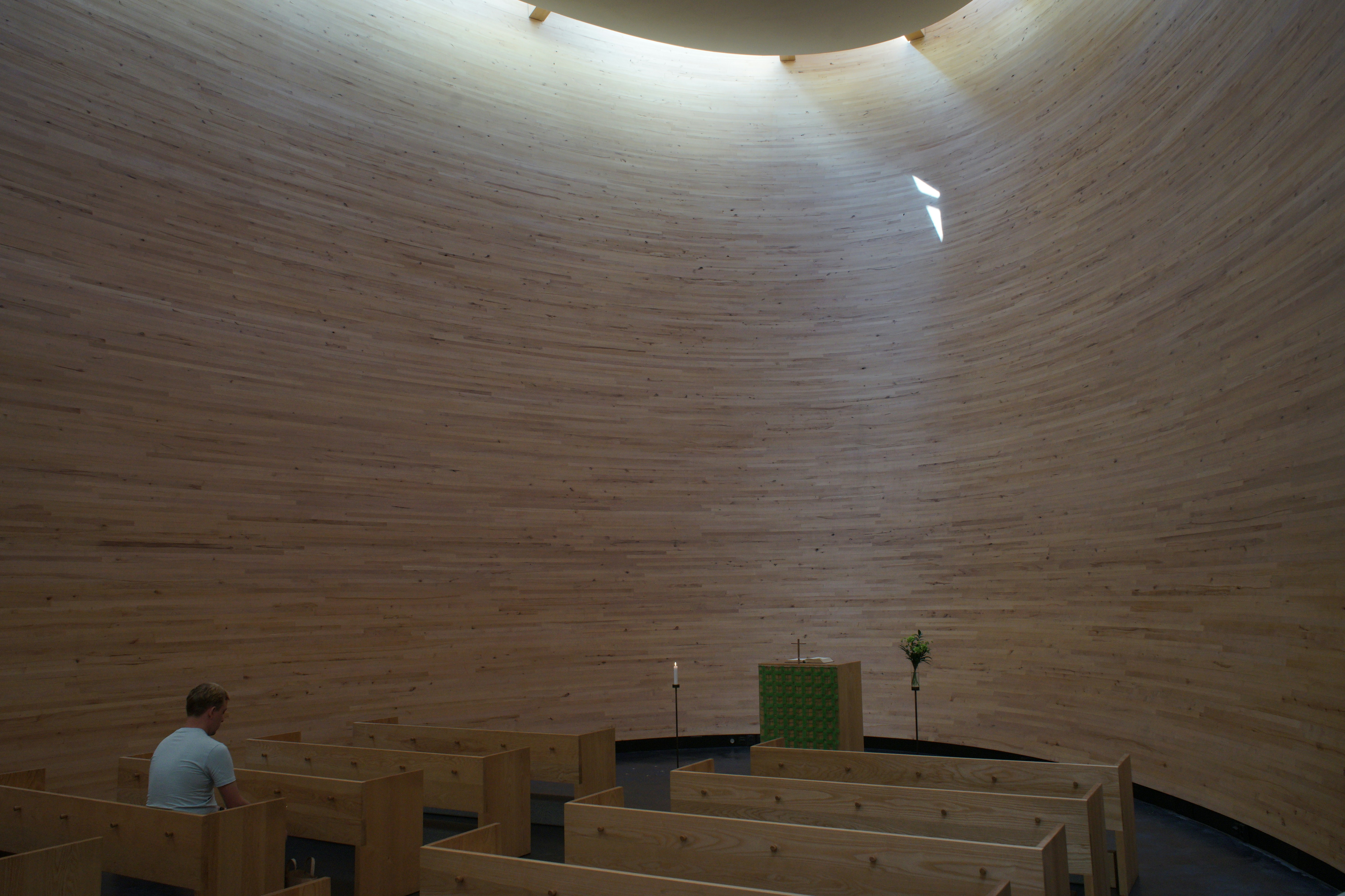 Cylindrical Chapel; Rows of Benches Recede Toward an Altar by a Single Plant