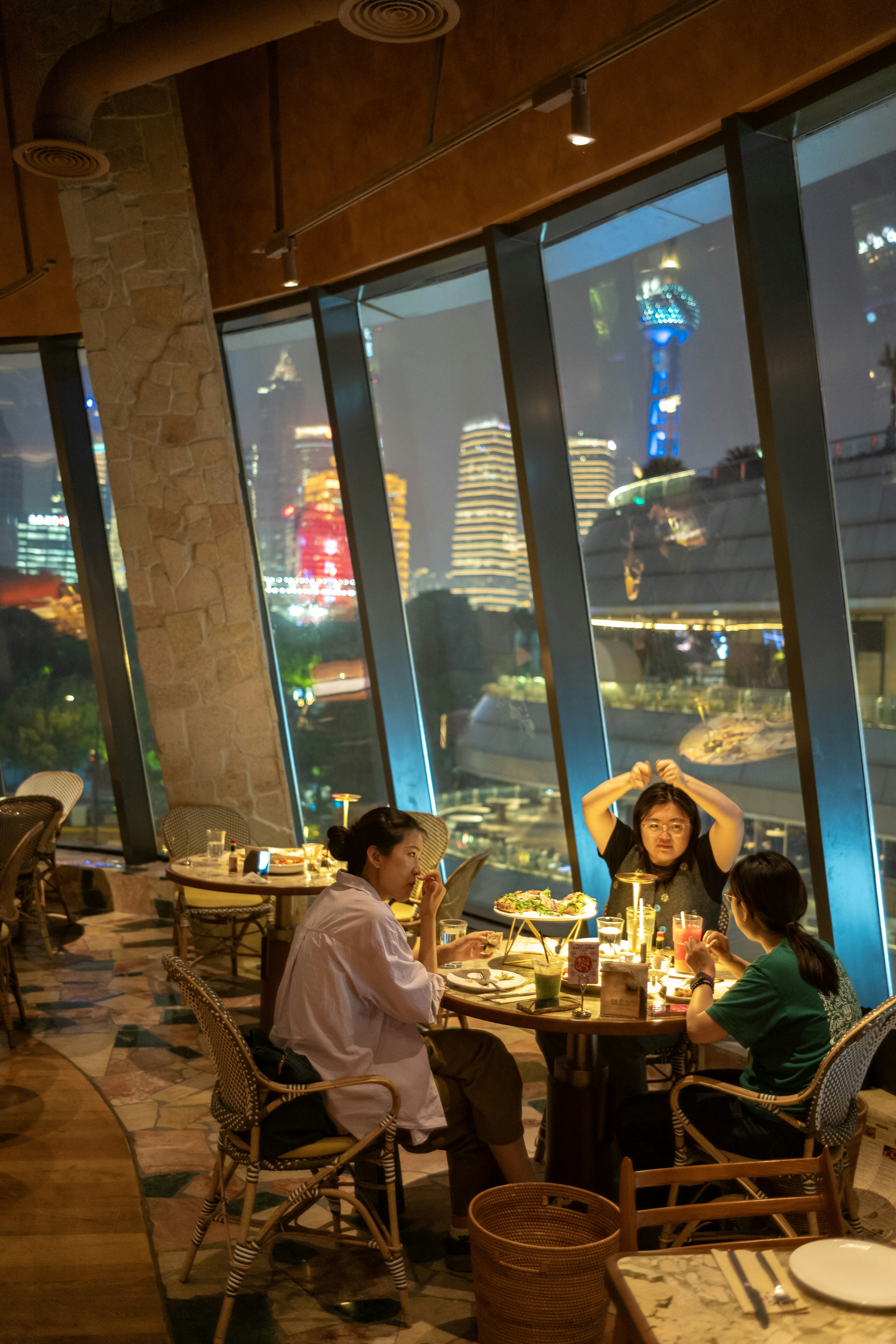 Evening Confidences at a Glass-Front Café Overlooking Neon Skyline