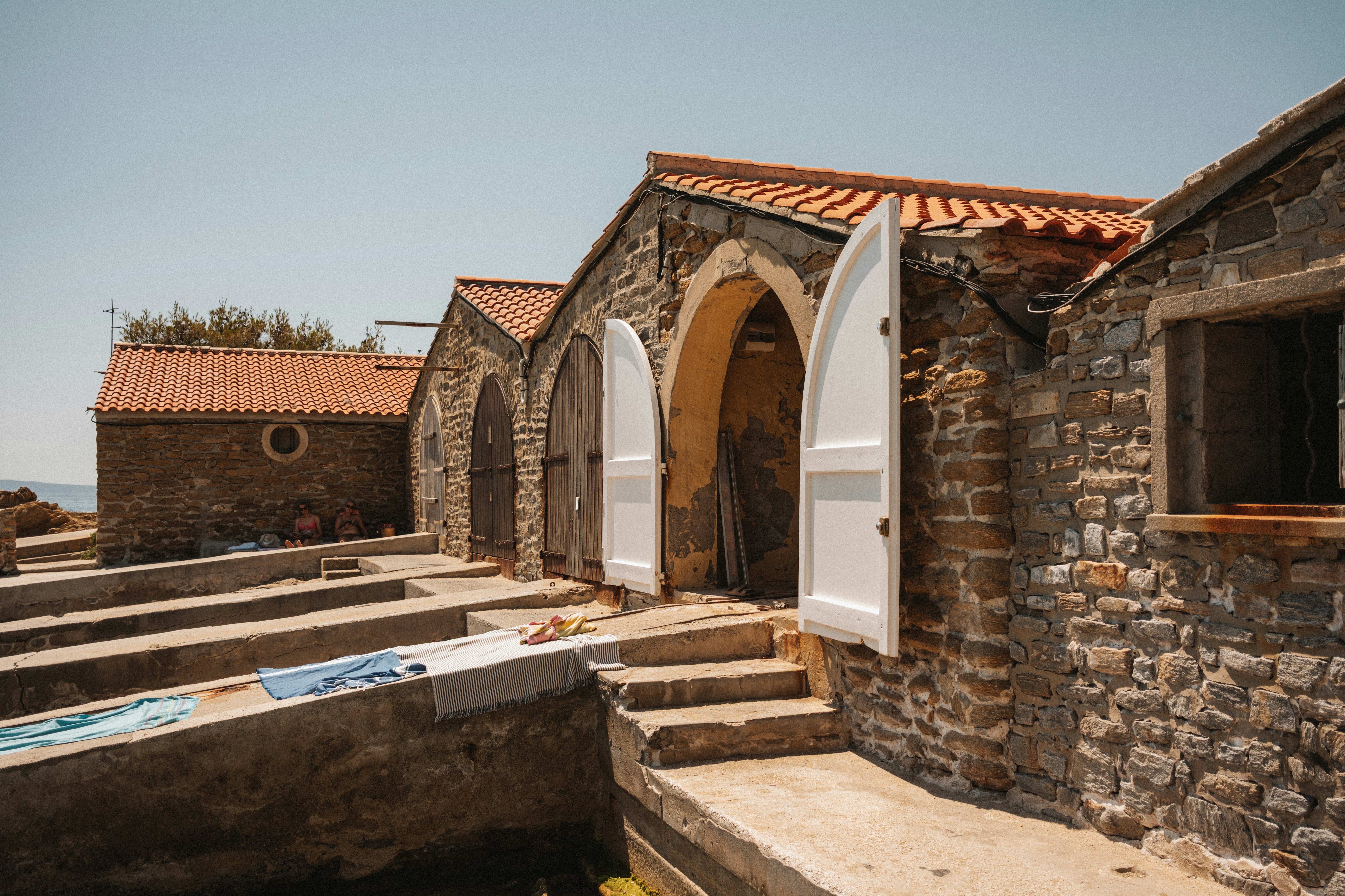 Arched Al fresco: White Doors Framing a Sunlit Stone Courtyard