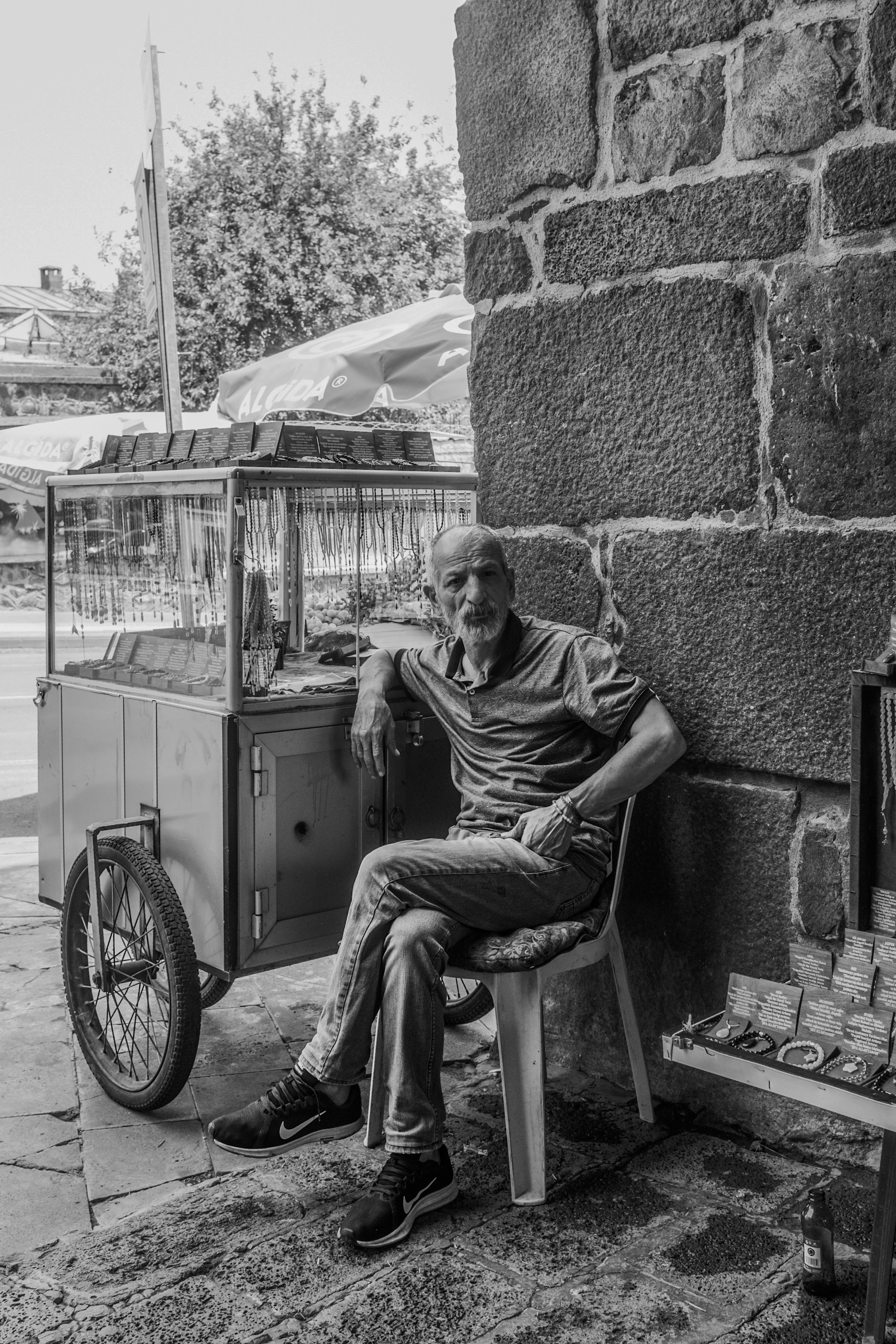 Street Vendor of Quiet Resilience under Brick Pillar