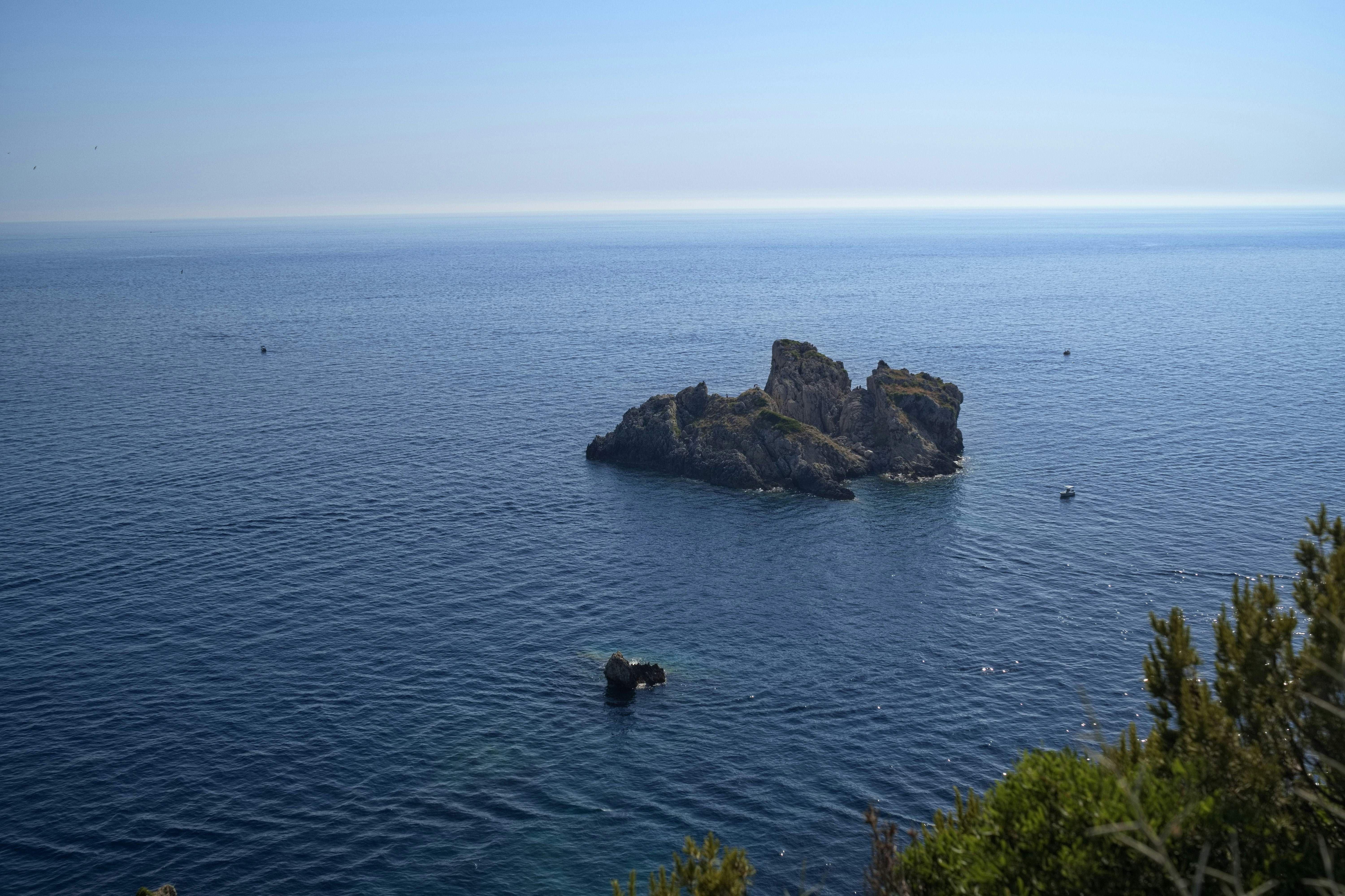 Rock outcrop mid-ocean under a clear horizon