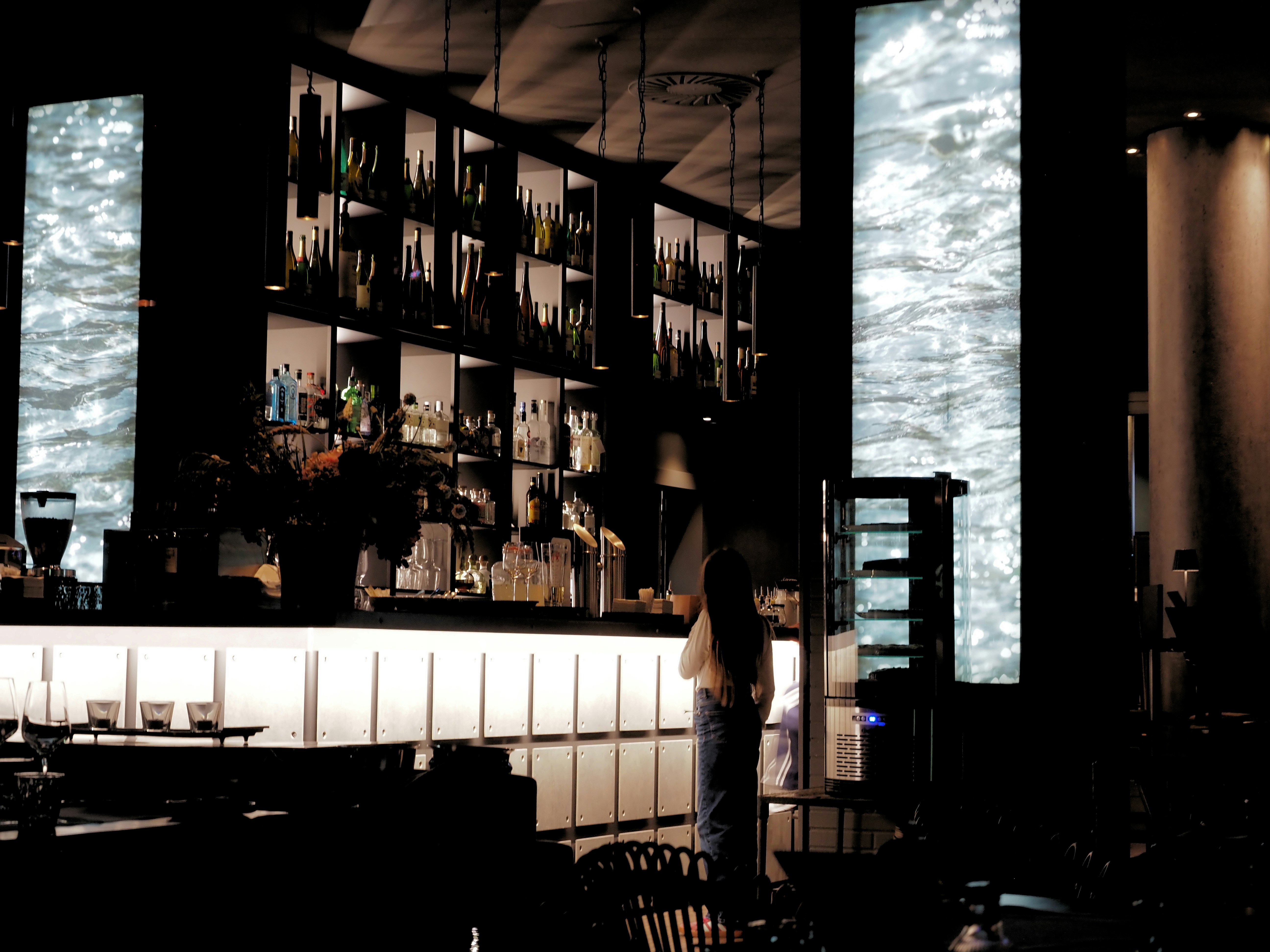 Bar Glow: A Solo Figure at the Back Bar Under Cool Glass Panels