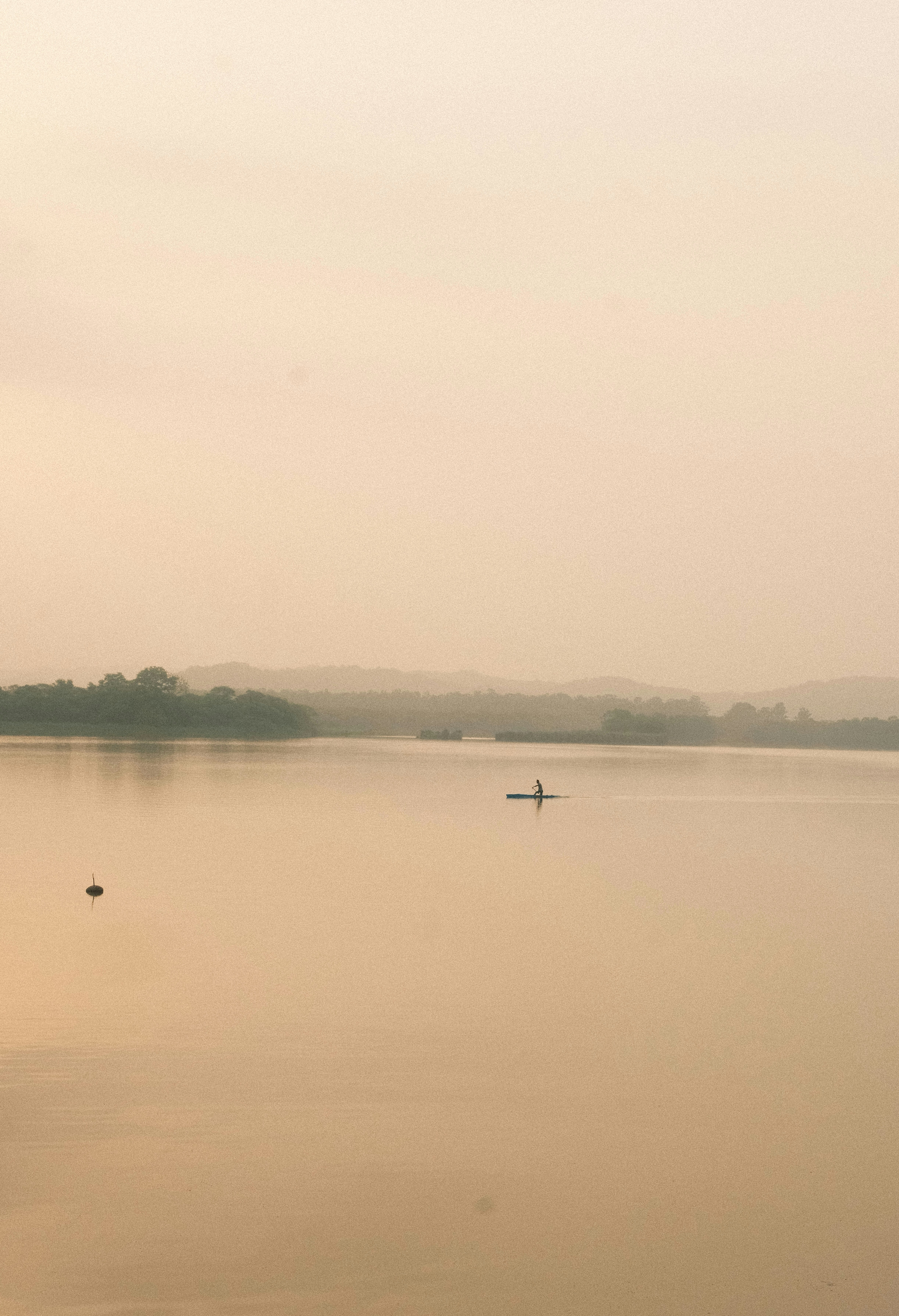 Silhouette of a Lone Rowing Figure Across Quiet Water at Dawn