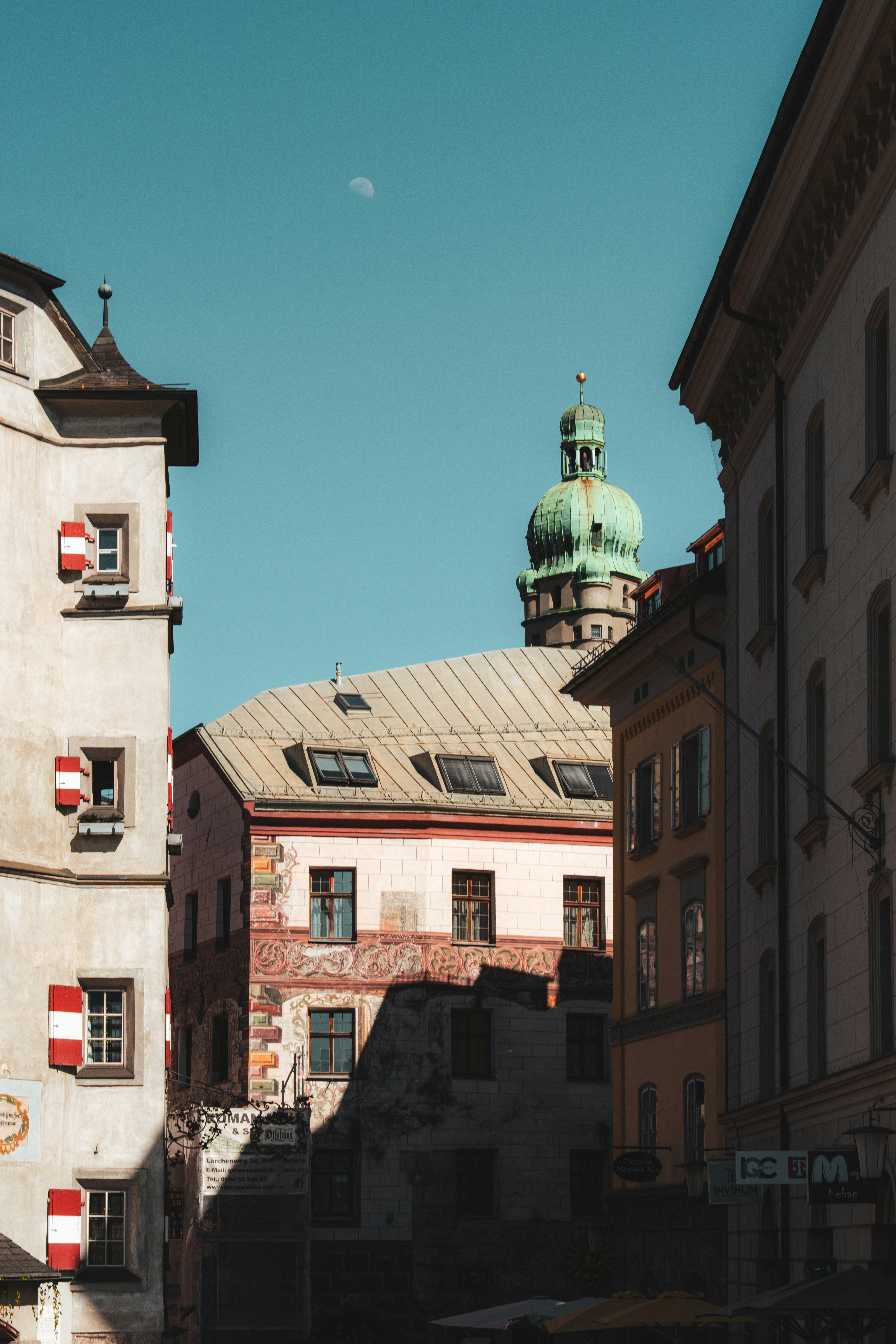 Green dome over aged facades: a sunlit street framed by history
