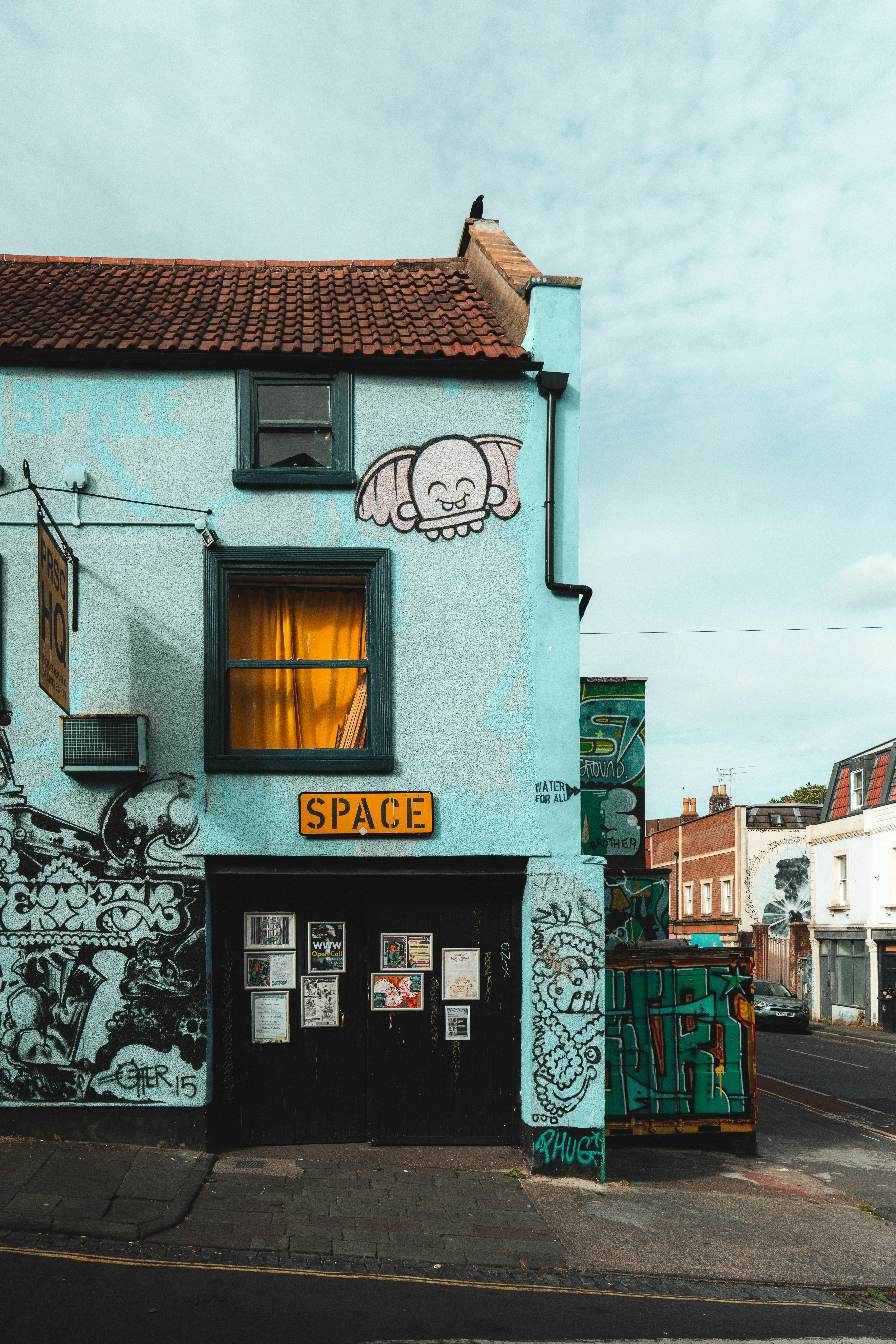 Graffitied Corner: The Bright Blue House with a Cartoon Emblem