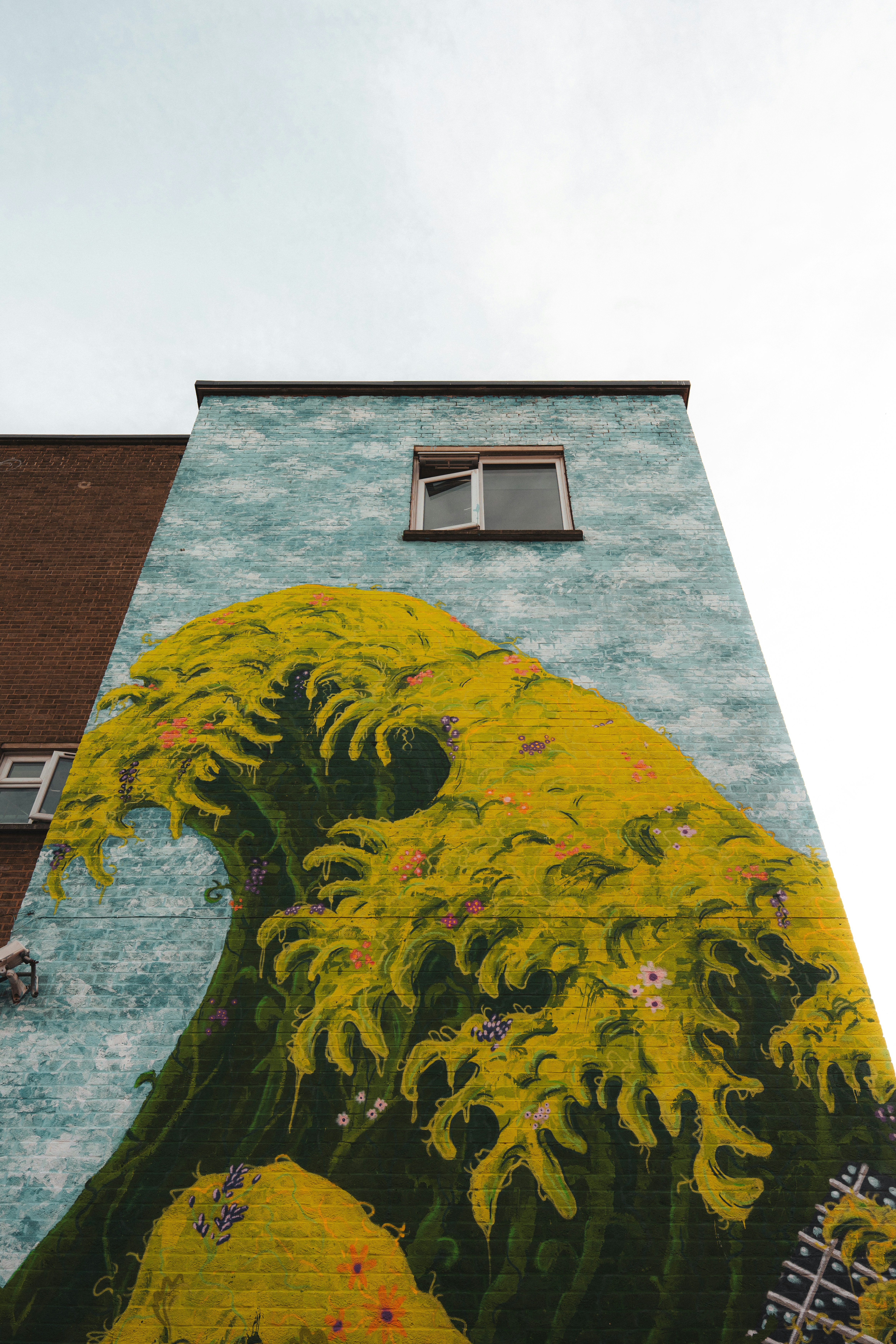 Vibrant mural climbs a sunlit brick facade