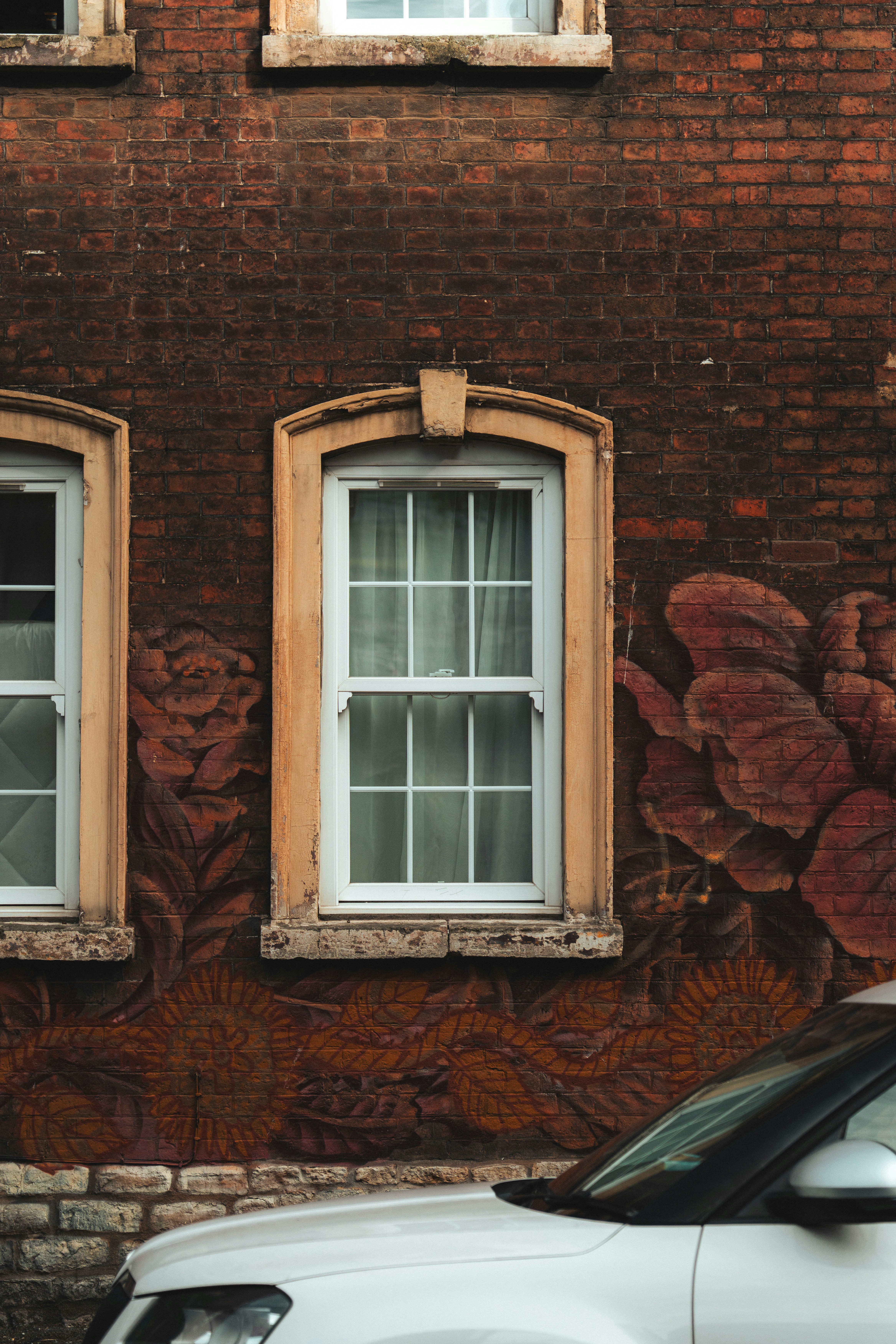 Brick Wall Portrait: Window Arch Framed by Floral Graffiti and Car