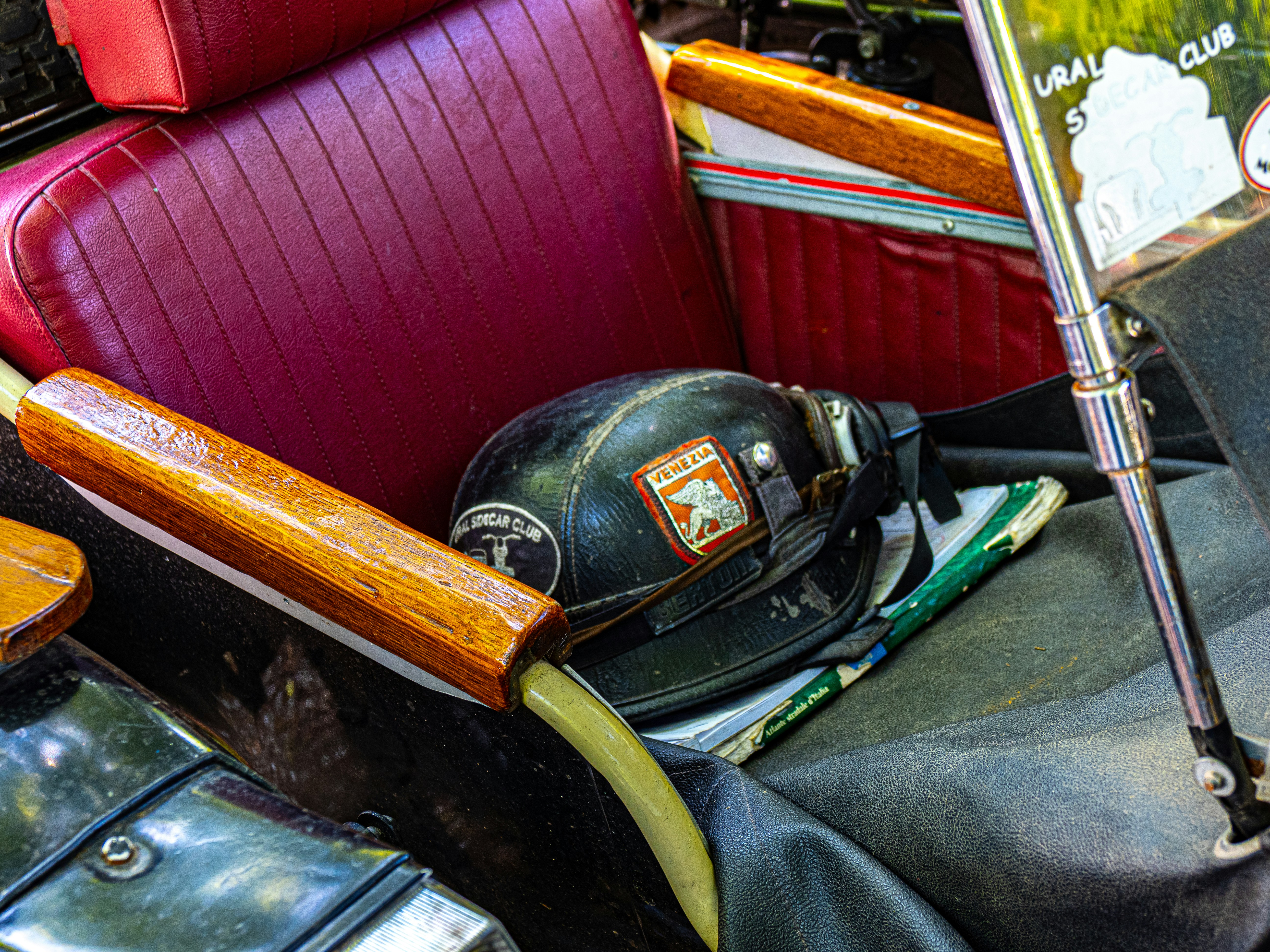Inside a Classic Car Cabin: Red Seat, Wooden Armrests, and a Vintage Helmet