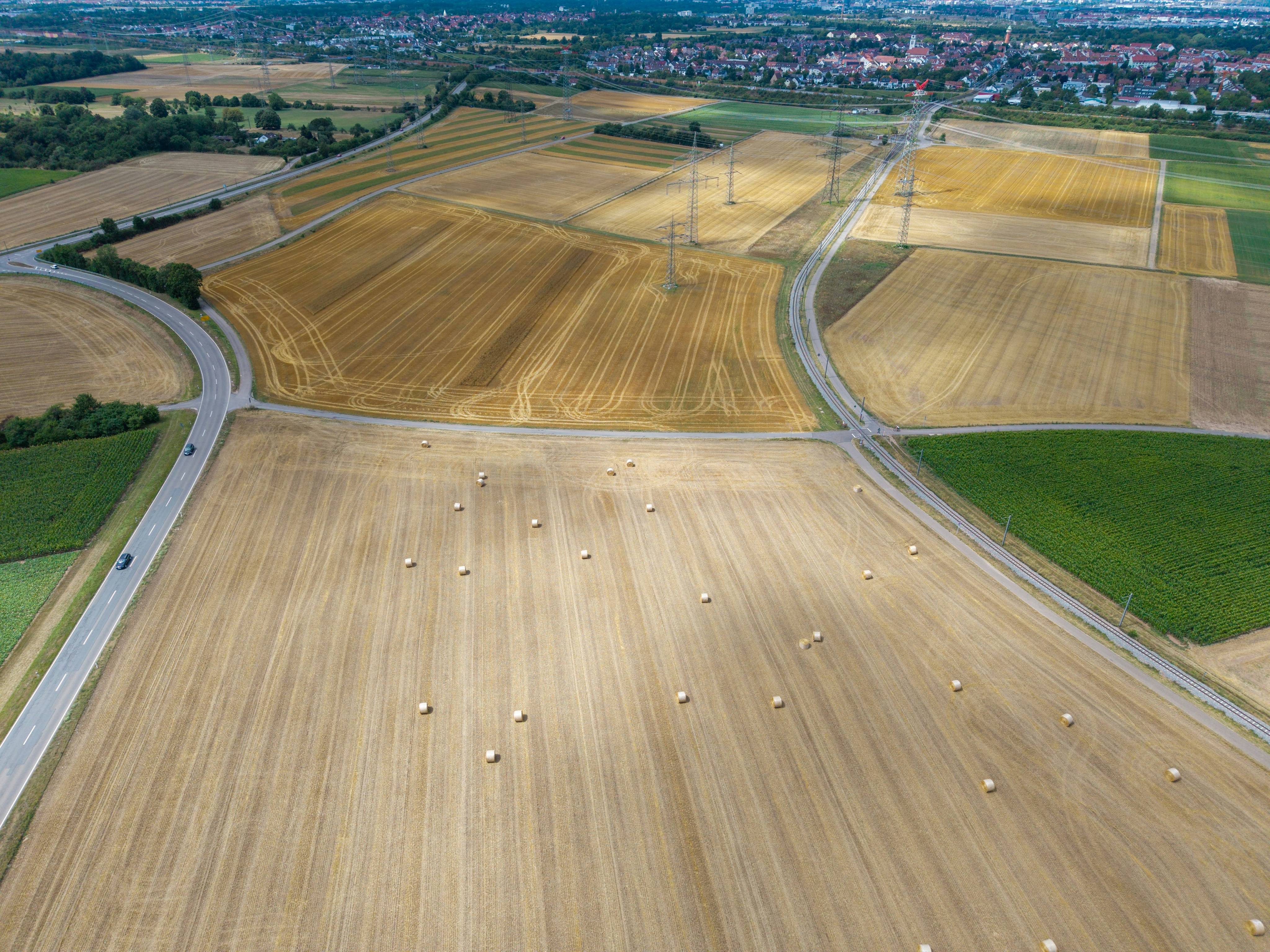 Harvested golden fields with hay bales, roads, and power lines.