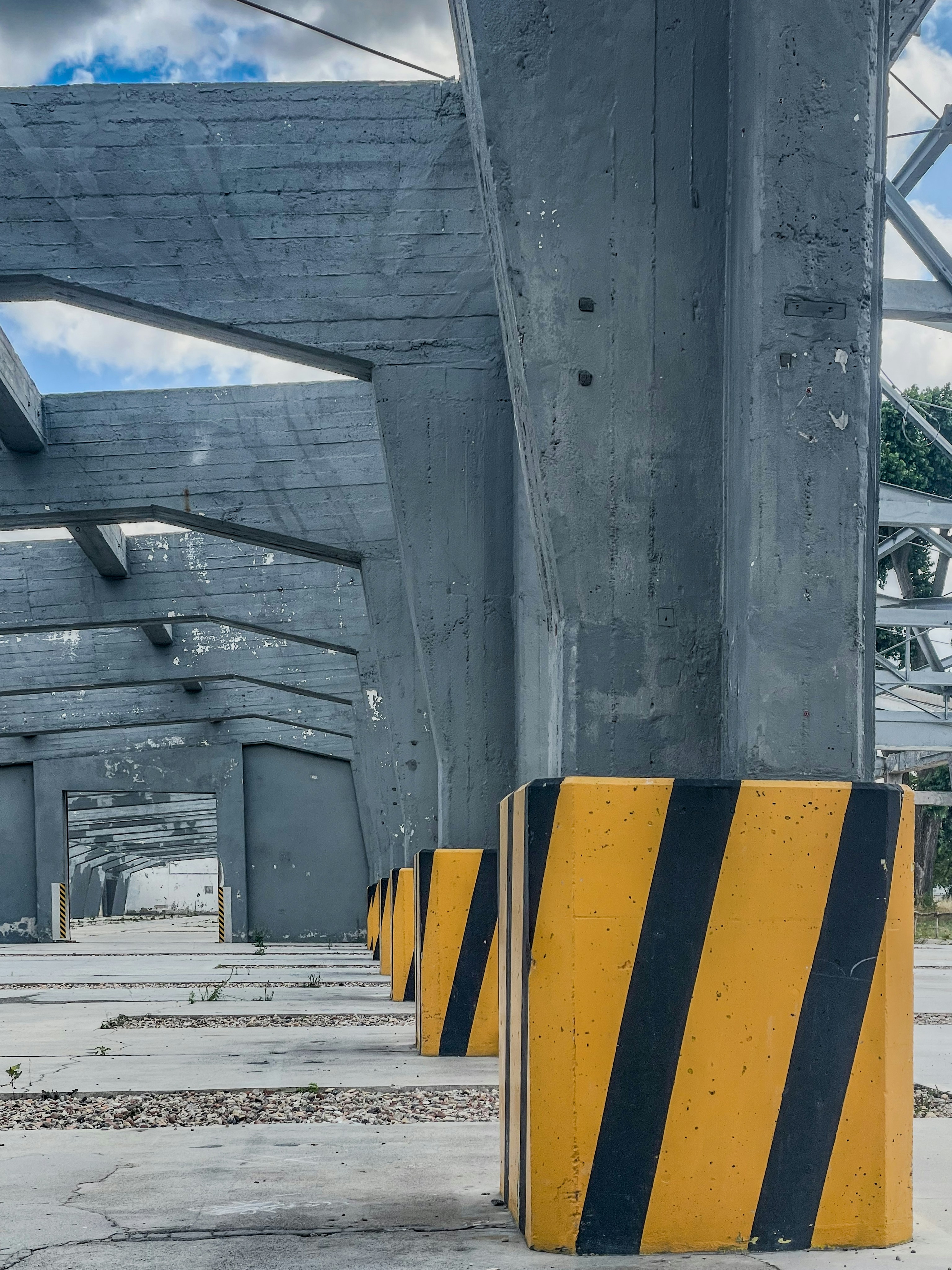 Concrete pillars and yellow striped barriers under a cloudy sky.