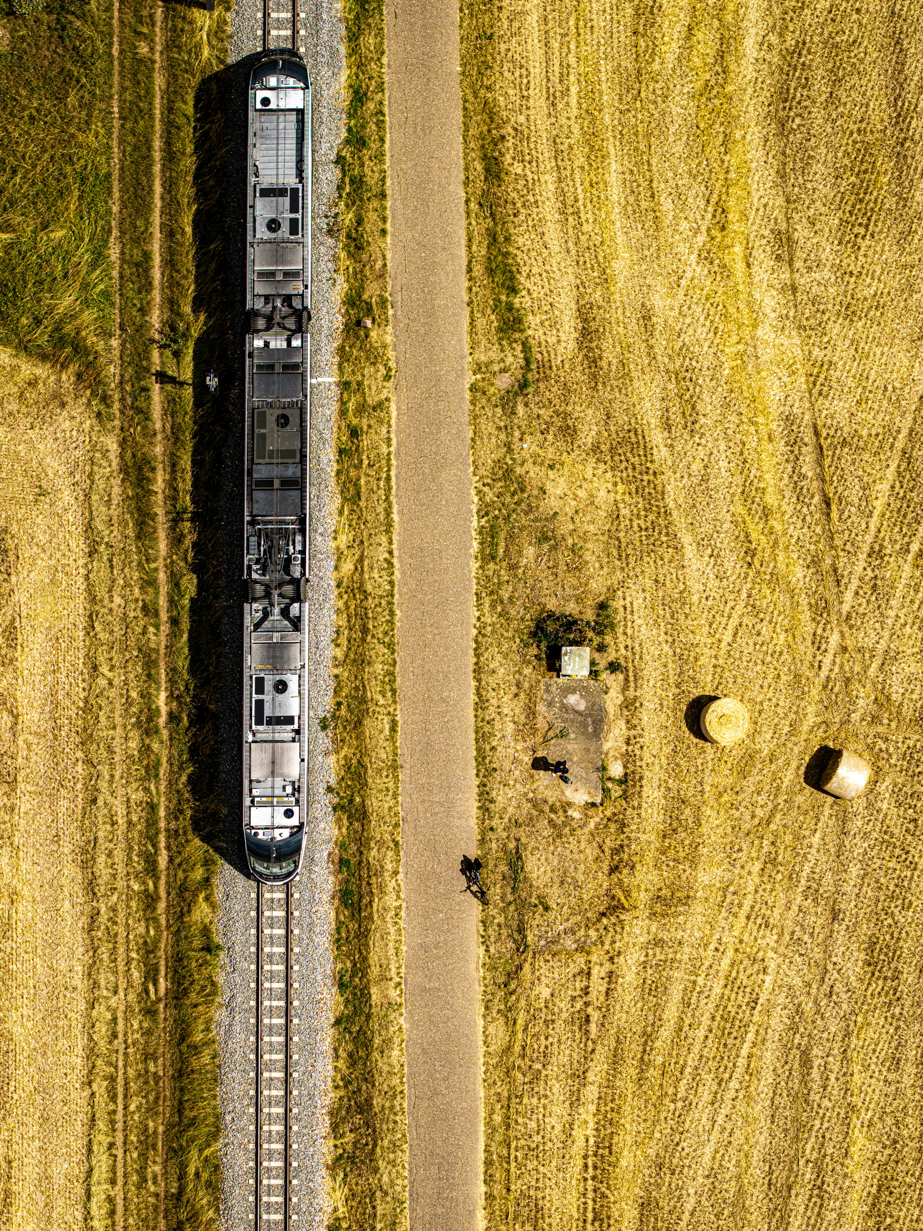 Narrow-gauge Journey: Aerial View of a Railcar and Field Corridor