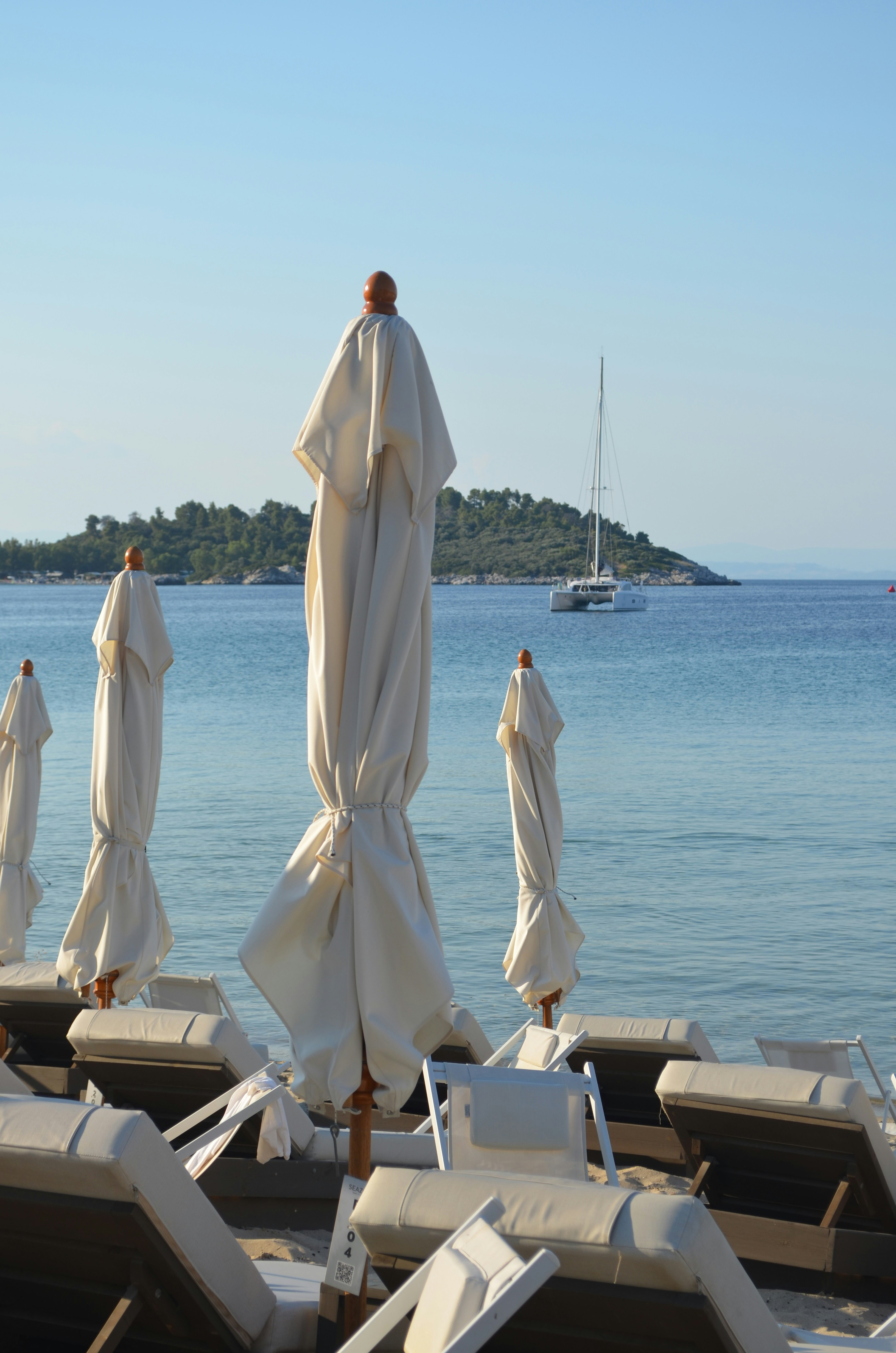 Creamy Coastal Silence: Lounge Chairs Stand Guard While Sails Rest in the Horizon