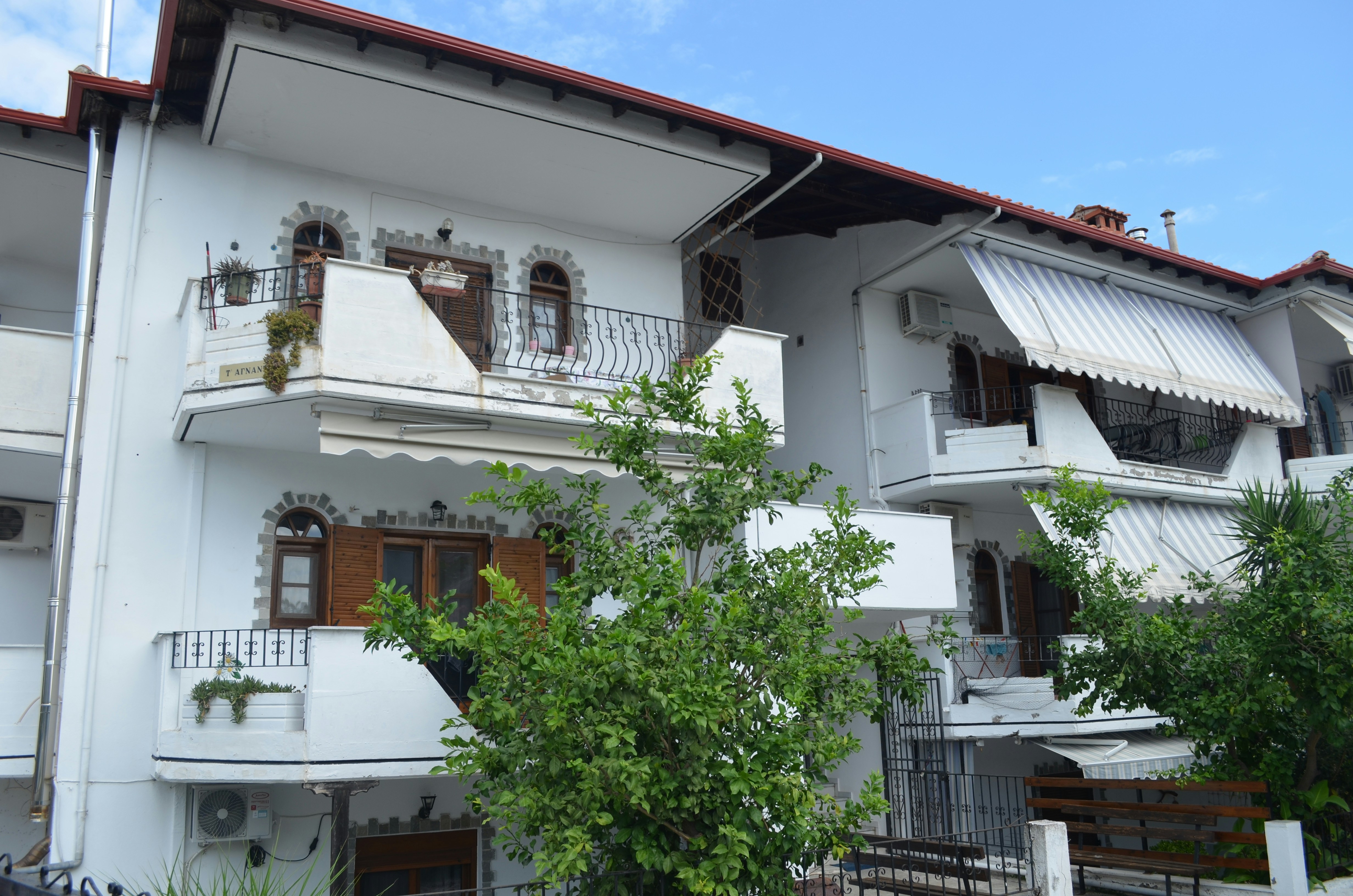 White residential façades and balconies framed by greenery