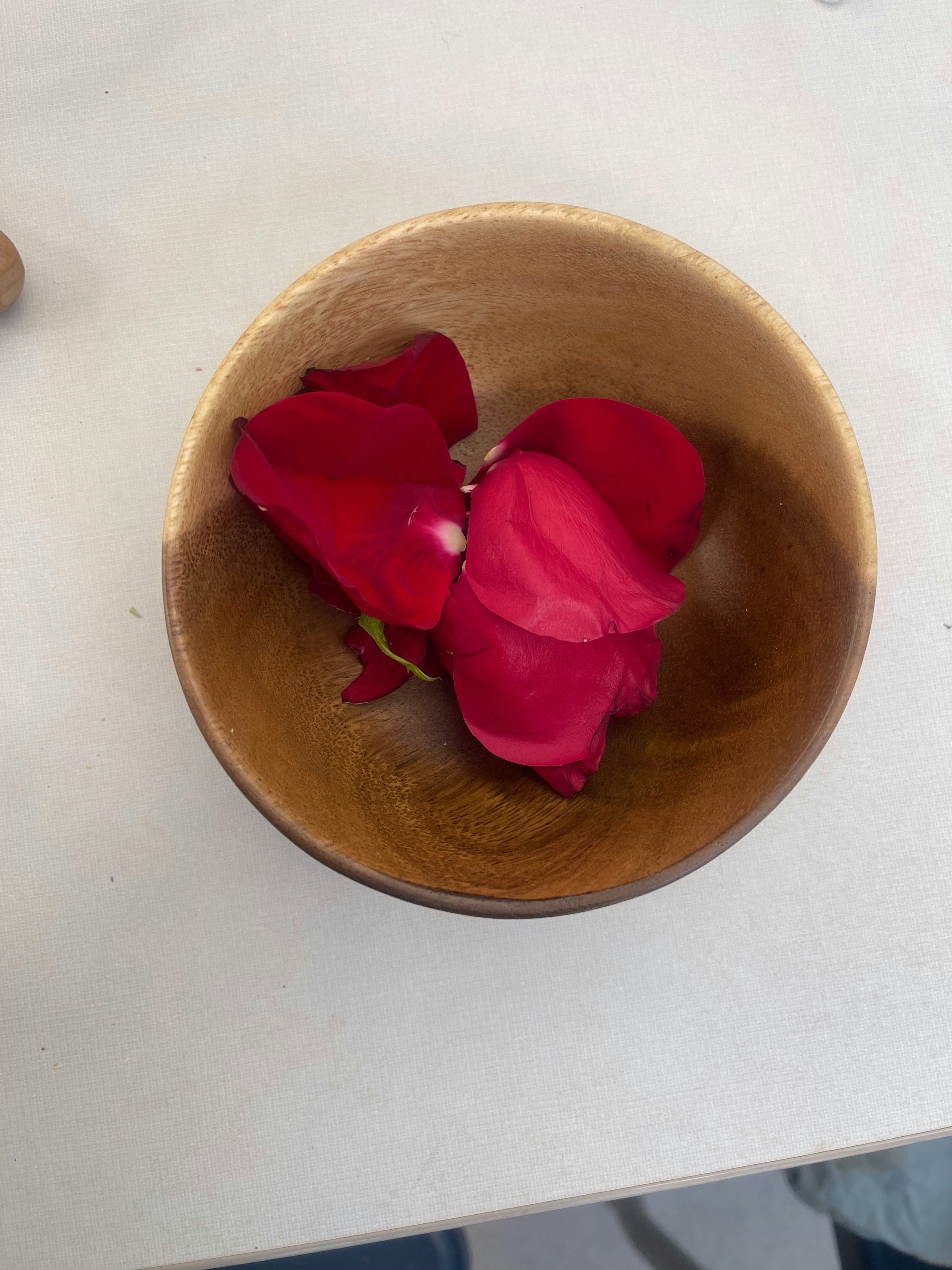 Red Petals in a Wooden Bowl: Simplicity on a Light Surface