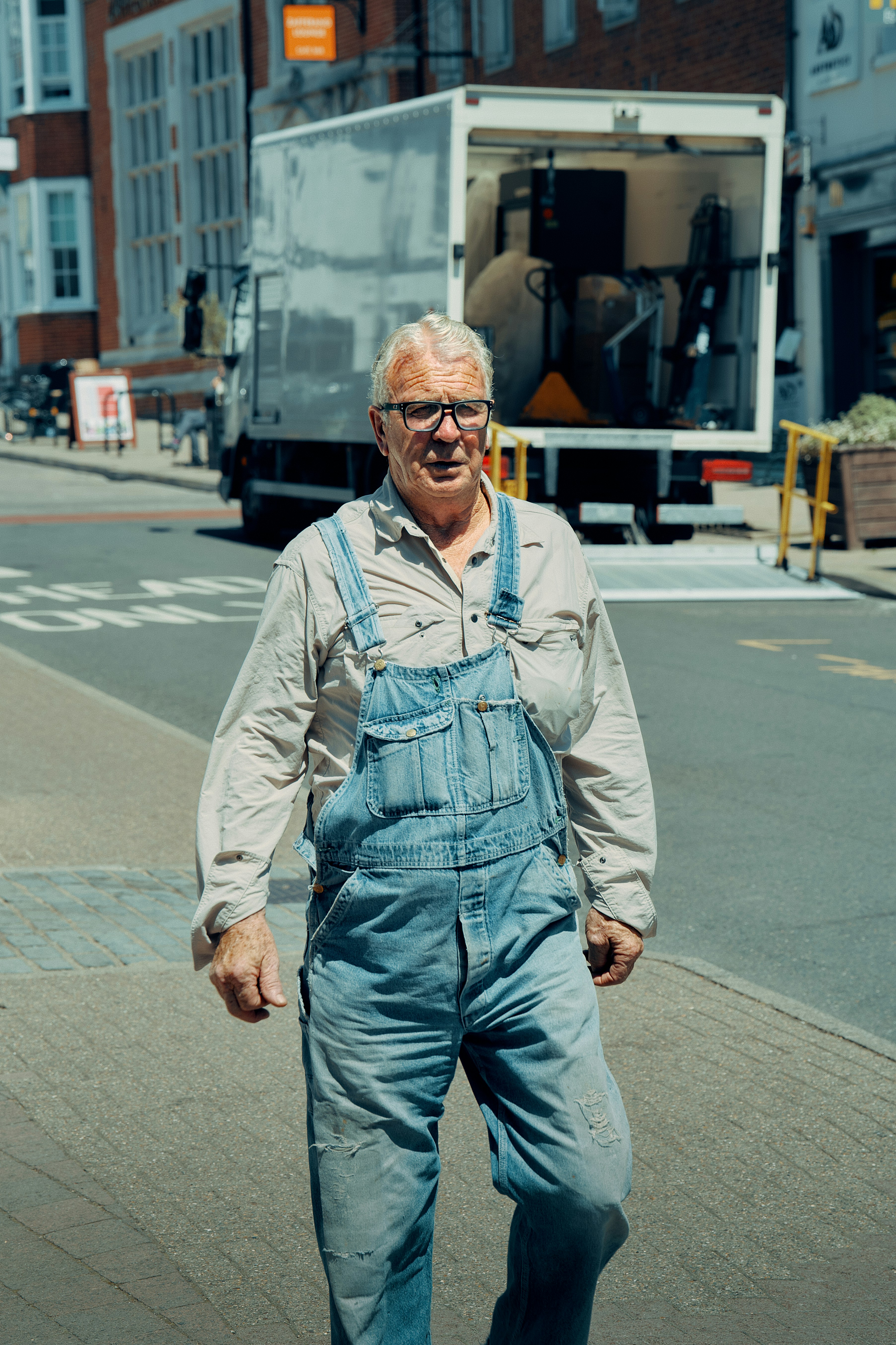 Old Hands, Busy Street: A Craftsman Waits by the Moving Truck