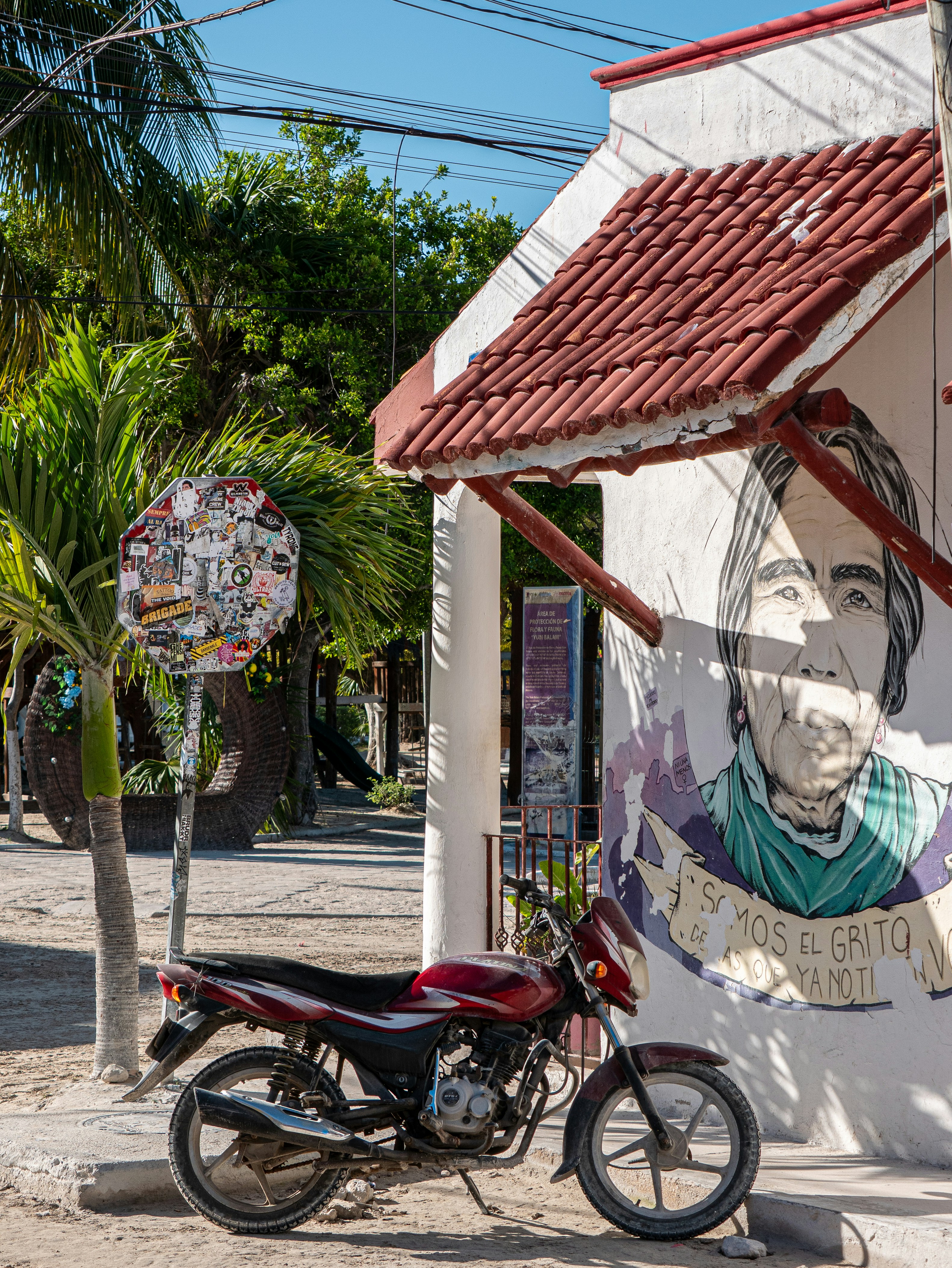 Mural Portrait and Motocycle Quietude by a Sunlit Wall
