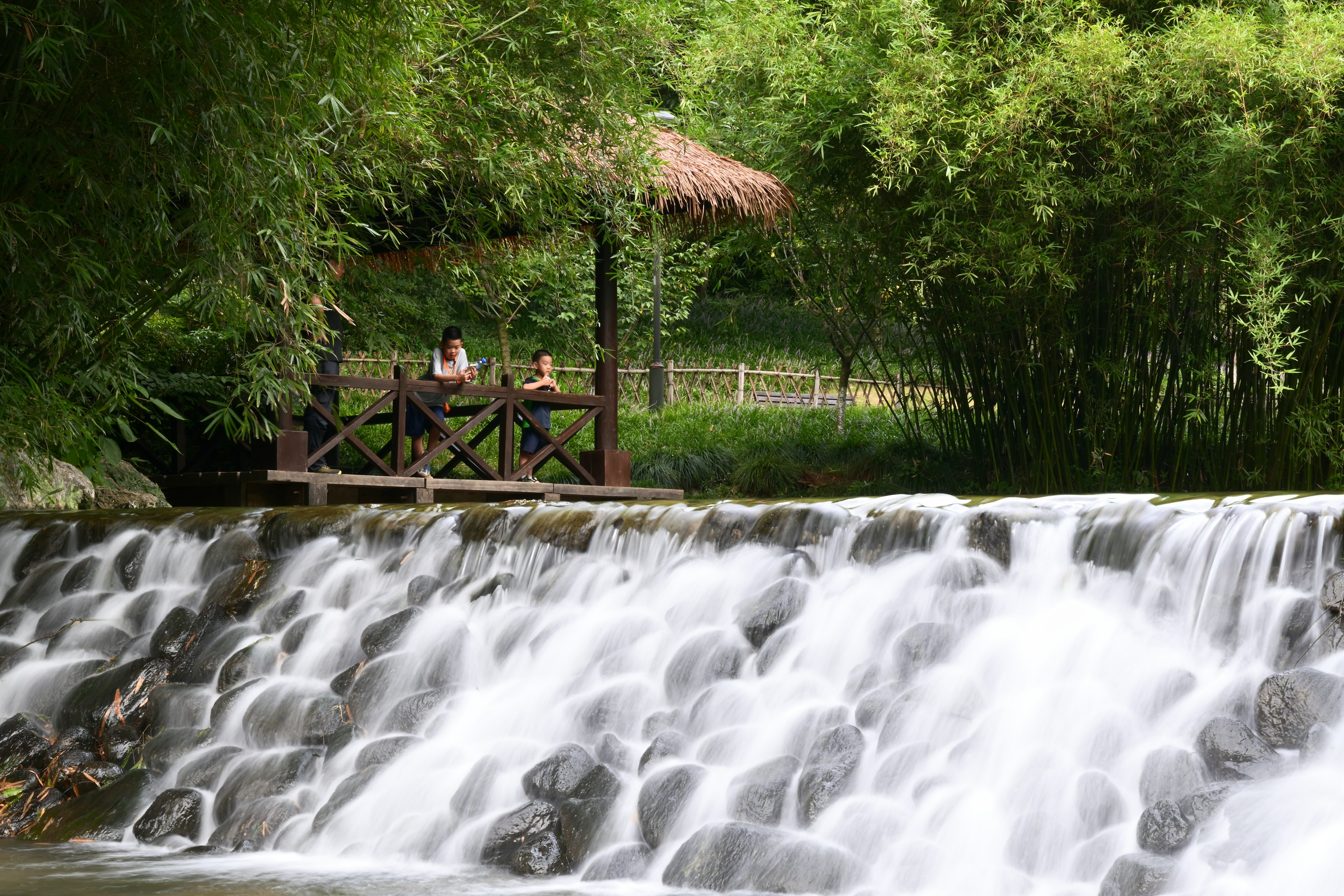 Waterfall Overlook: People in a thatched gazebo framed by cascading rapids