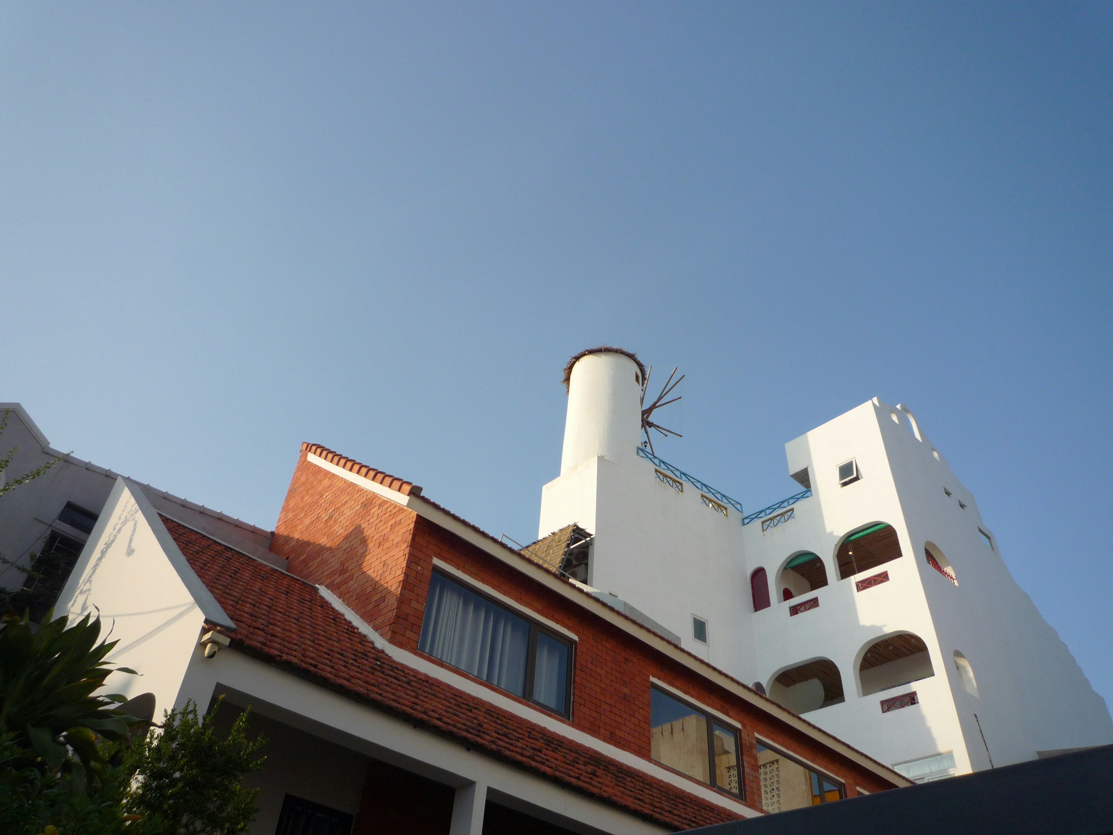 Sunlit Facade Convergence: White modern tower Meet Red-Tiled Roof