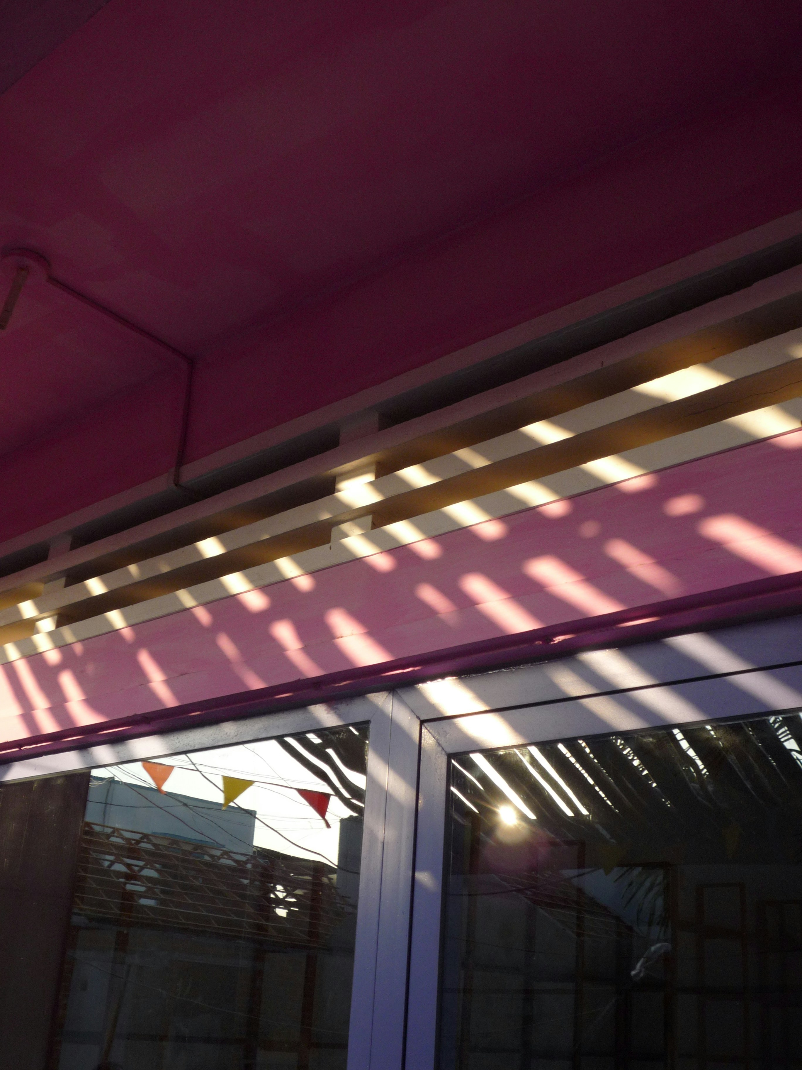 Pink storefront overhang with striped light pattern and glass doors