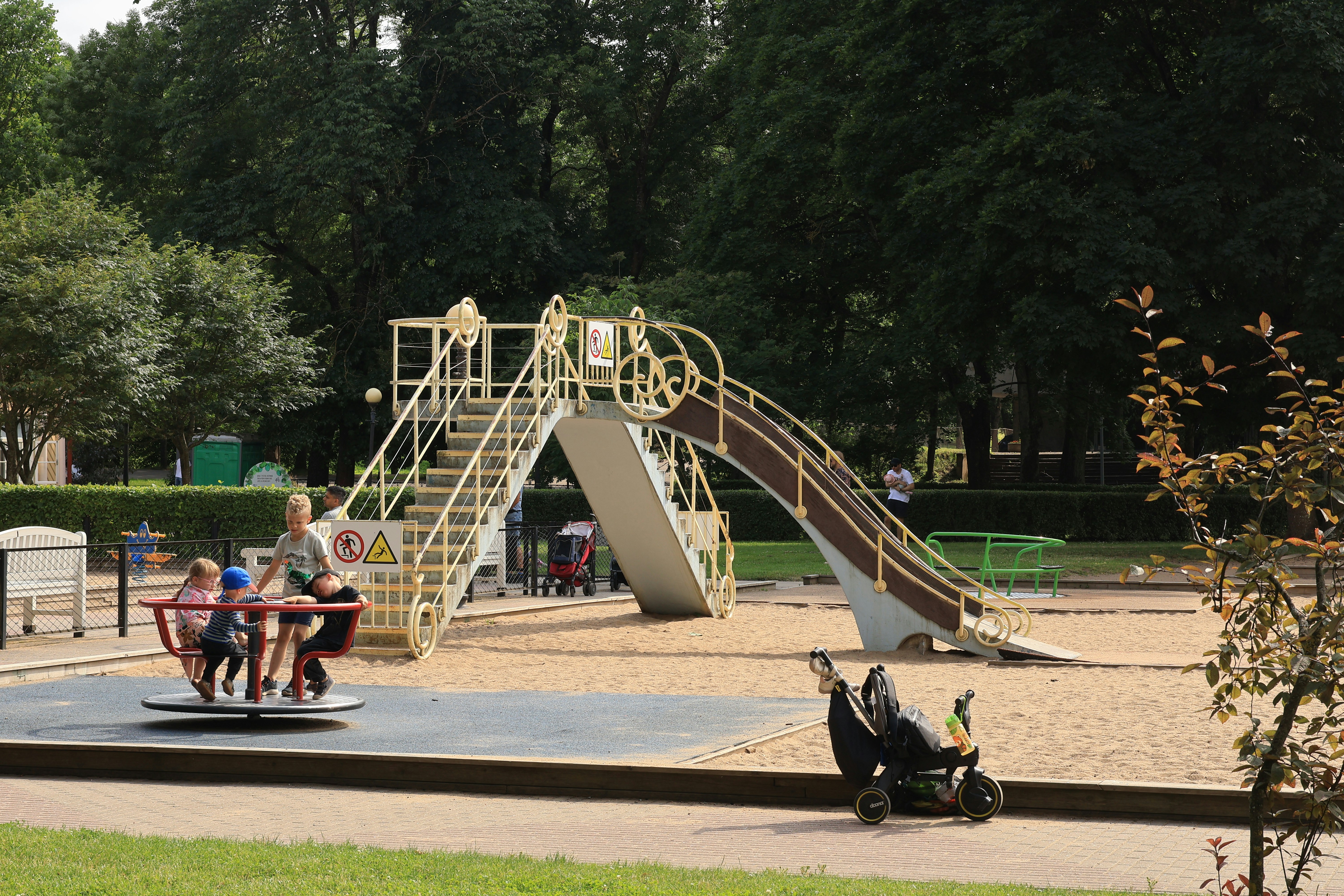 Playground Carousel: Children and Stroller in a Sunlit Park