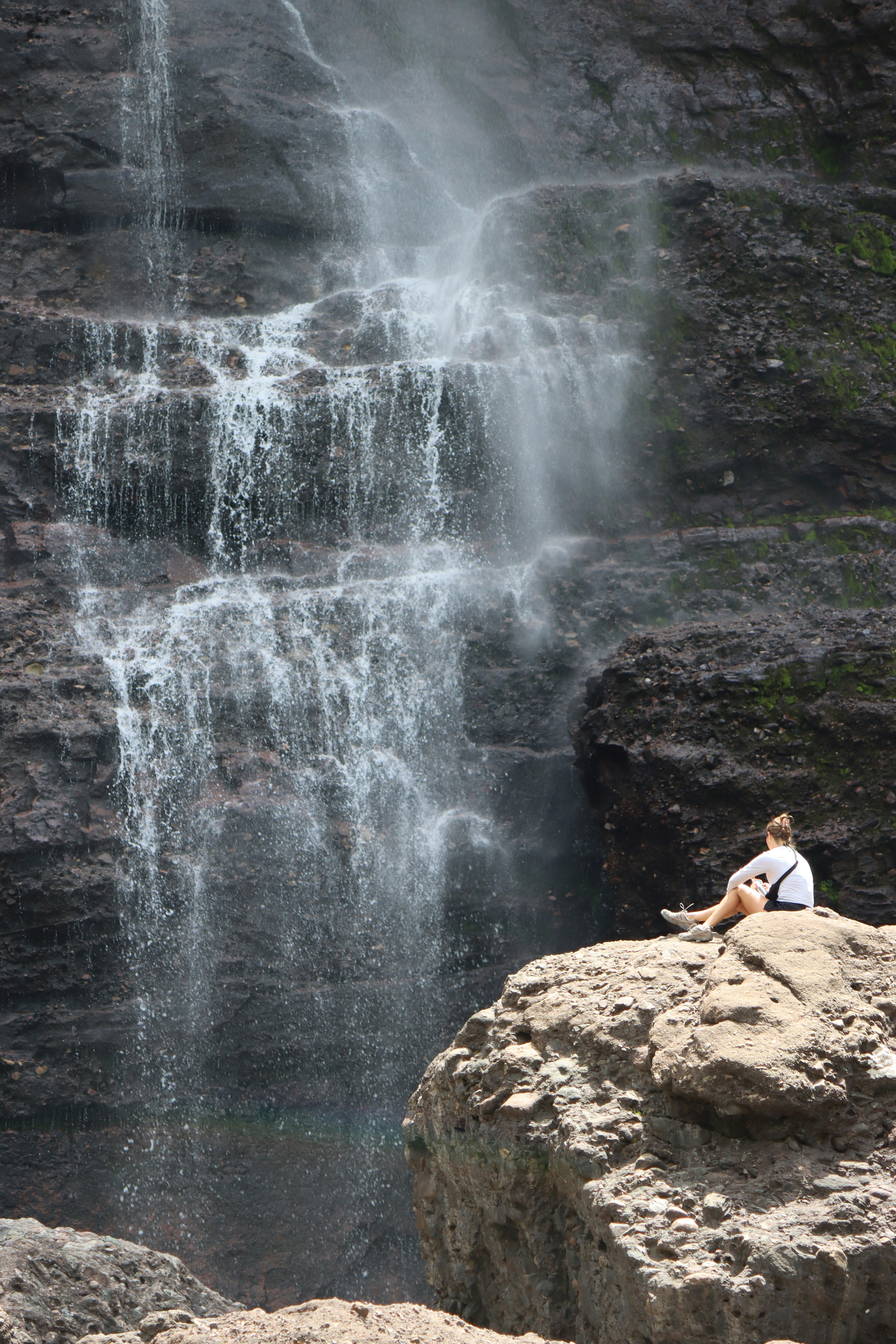 Eyes on the Edge: A Hiker Silhouette Against a Cascading Cliff