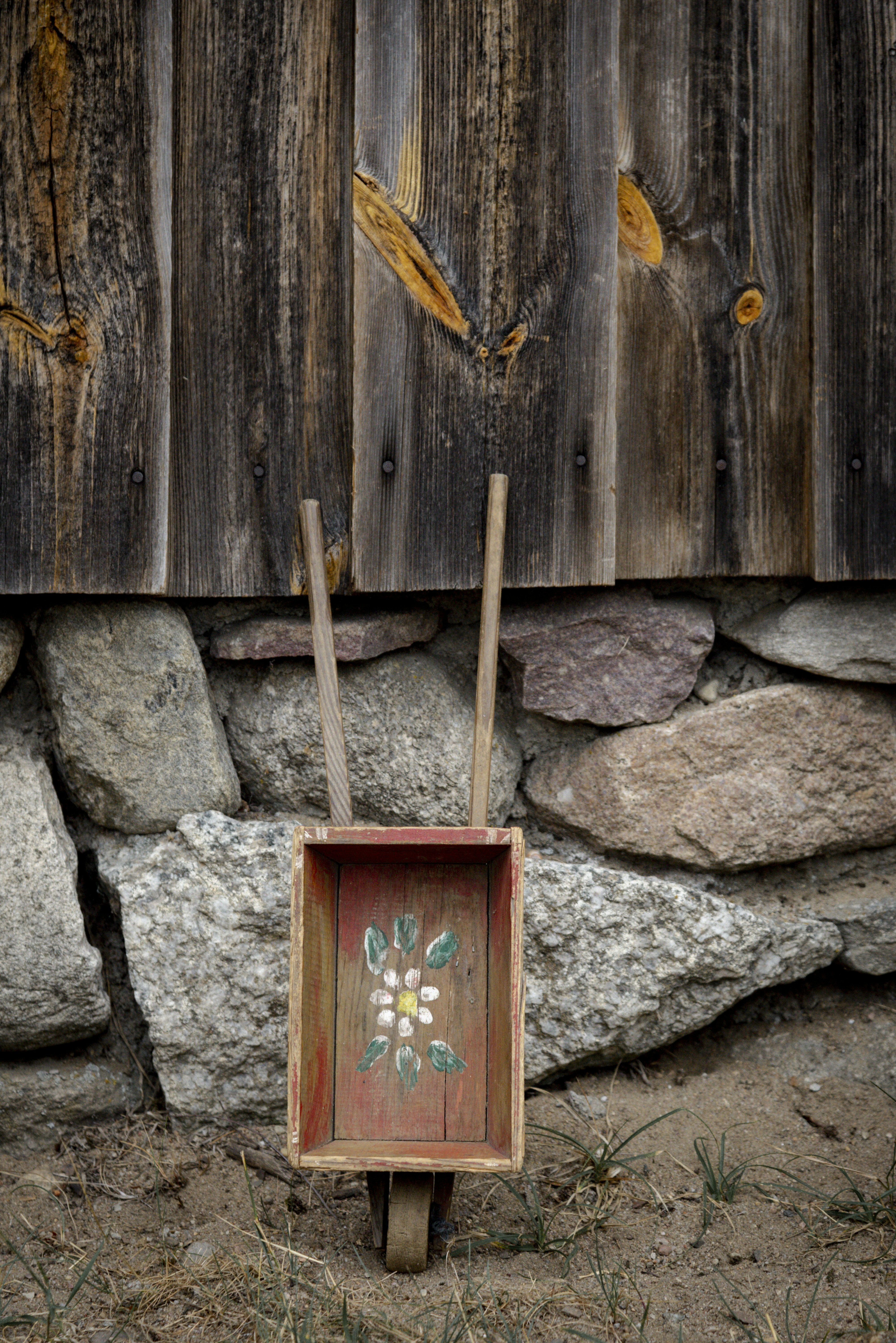 Wooden Box with Floral Motif on a Rugged Stone Wall