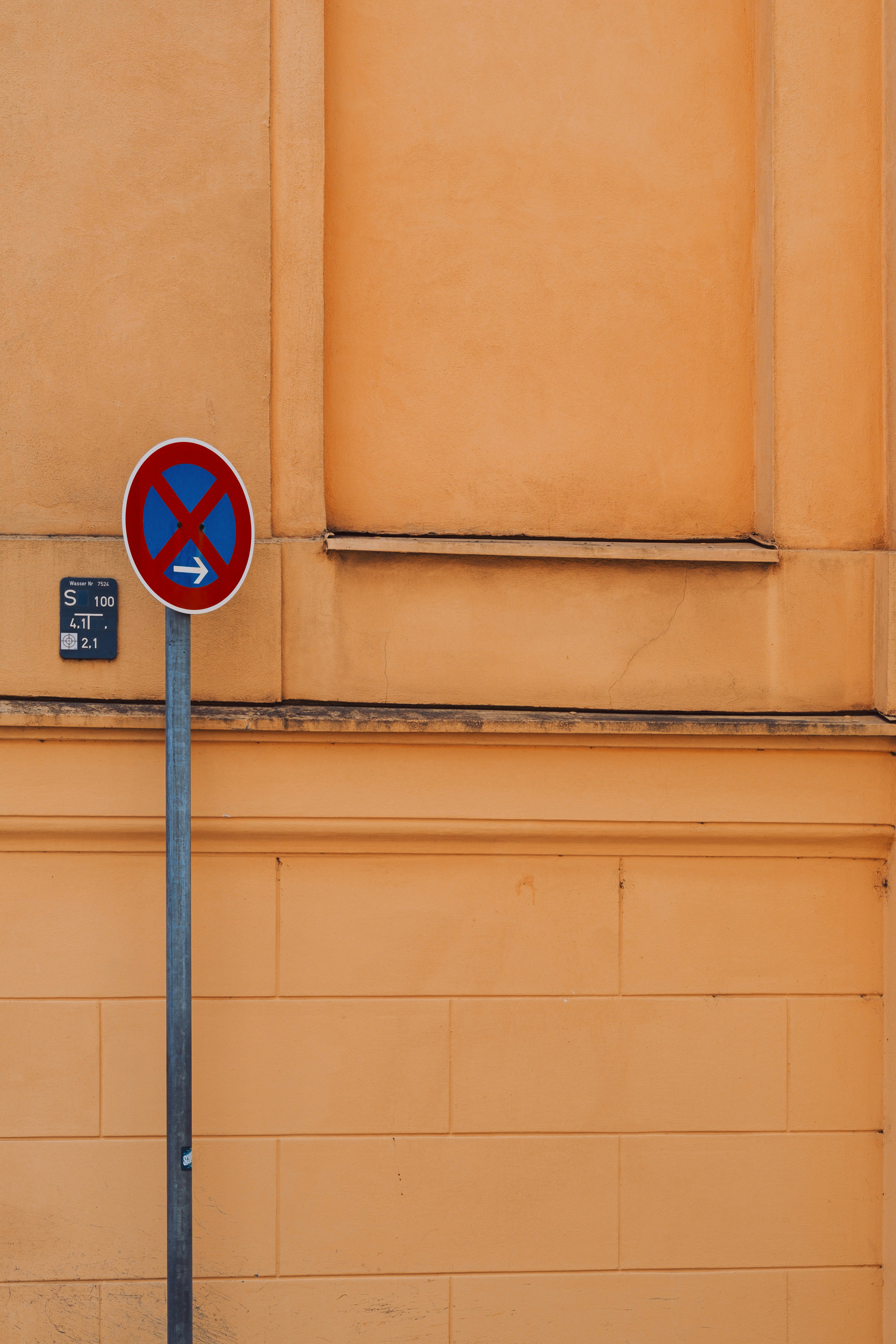 Orange Wall with No- Parking Sign: A Minimal Street Corner
