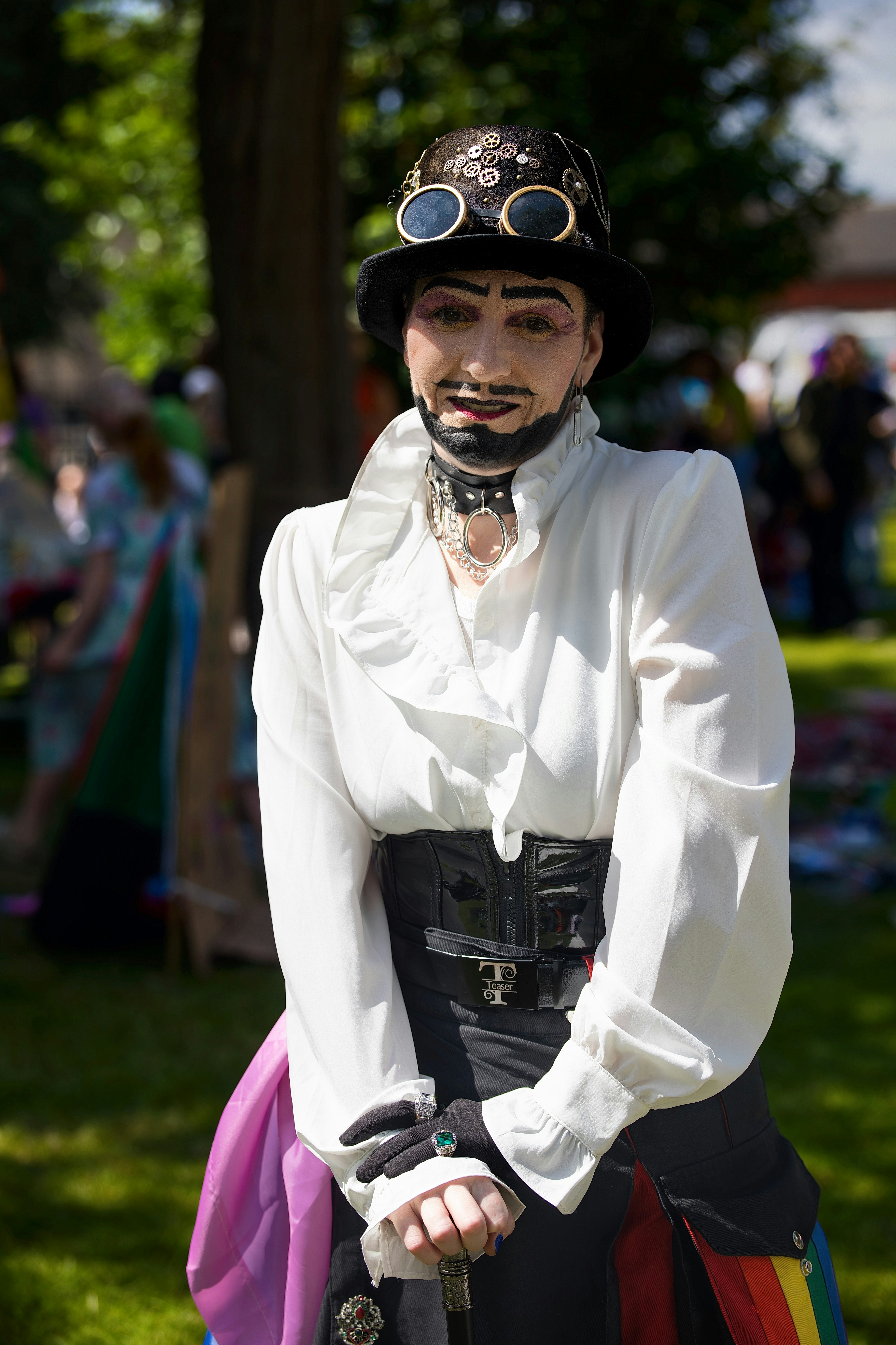Steampunk mime in white blouse and corseted black waistcoat at a sunny park