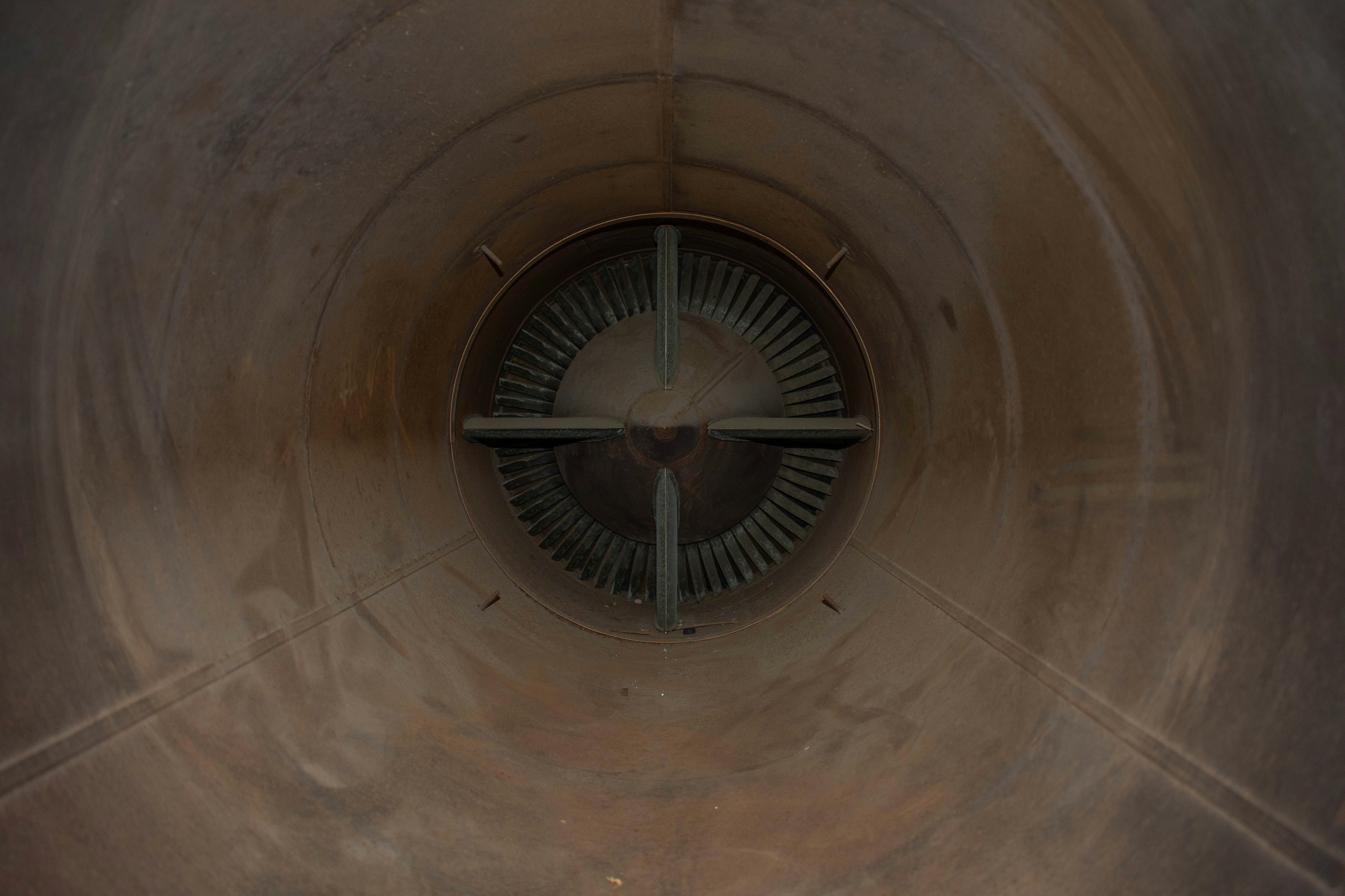 Industrial Vortex: Inside a Rusted Vent with a Central Fan