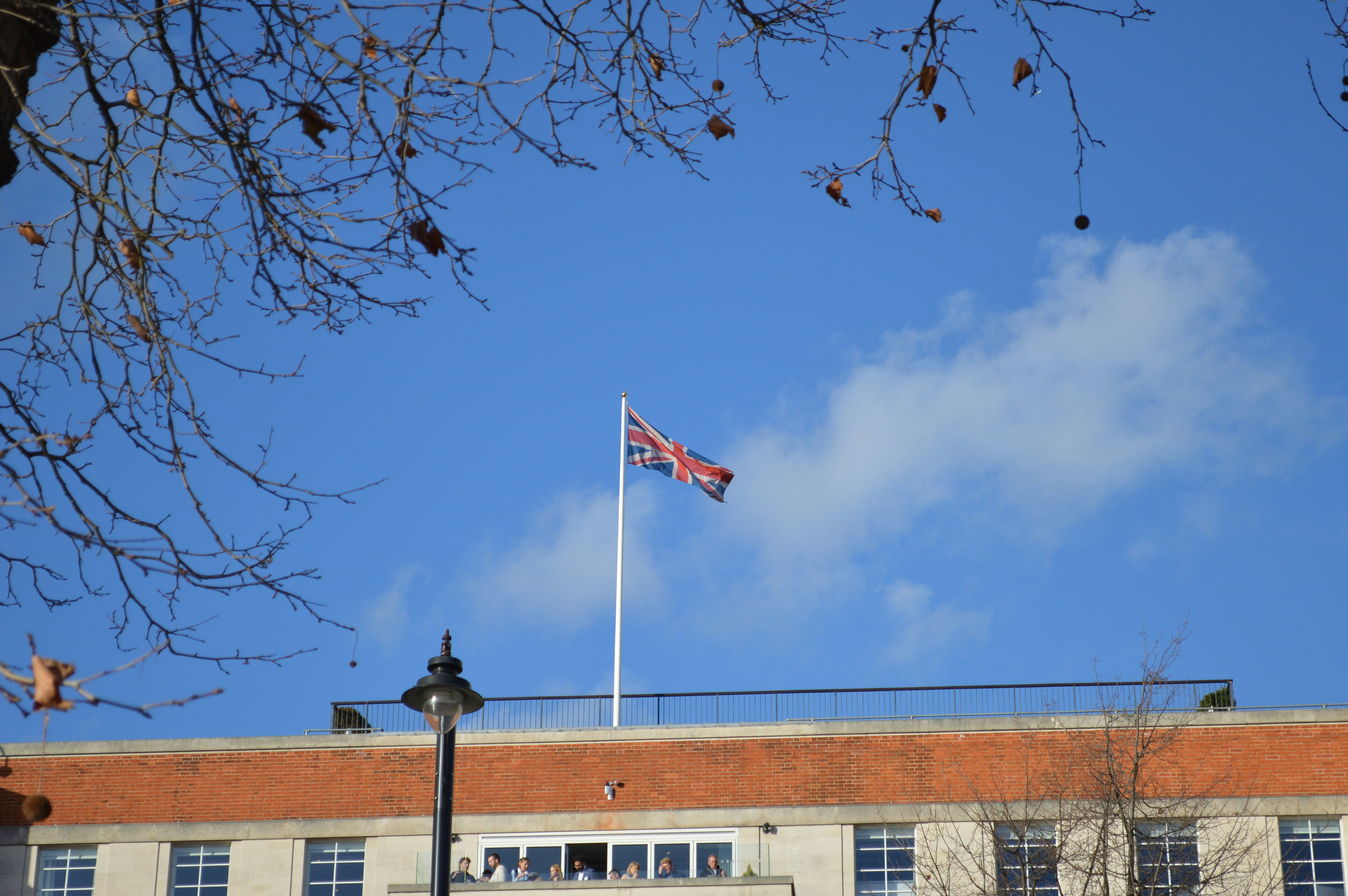 Flag Above an Urban Facade Under a Clear Blue Sky