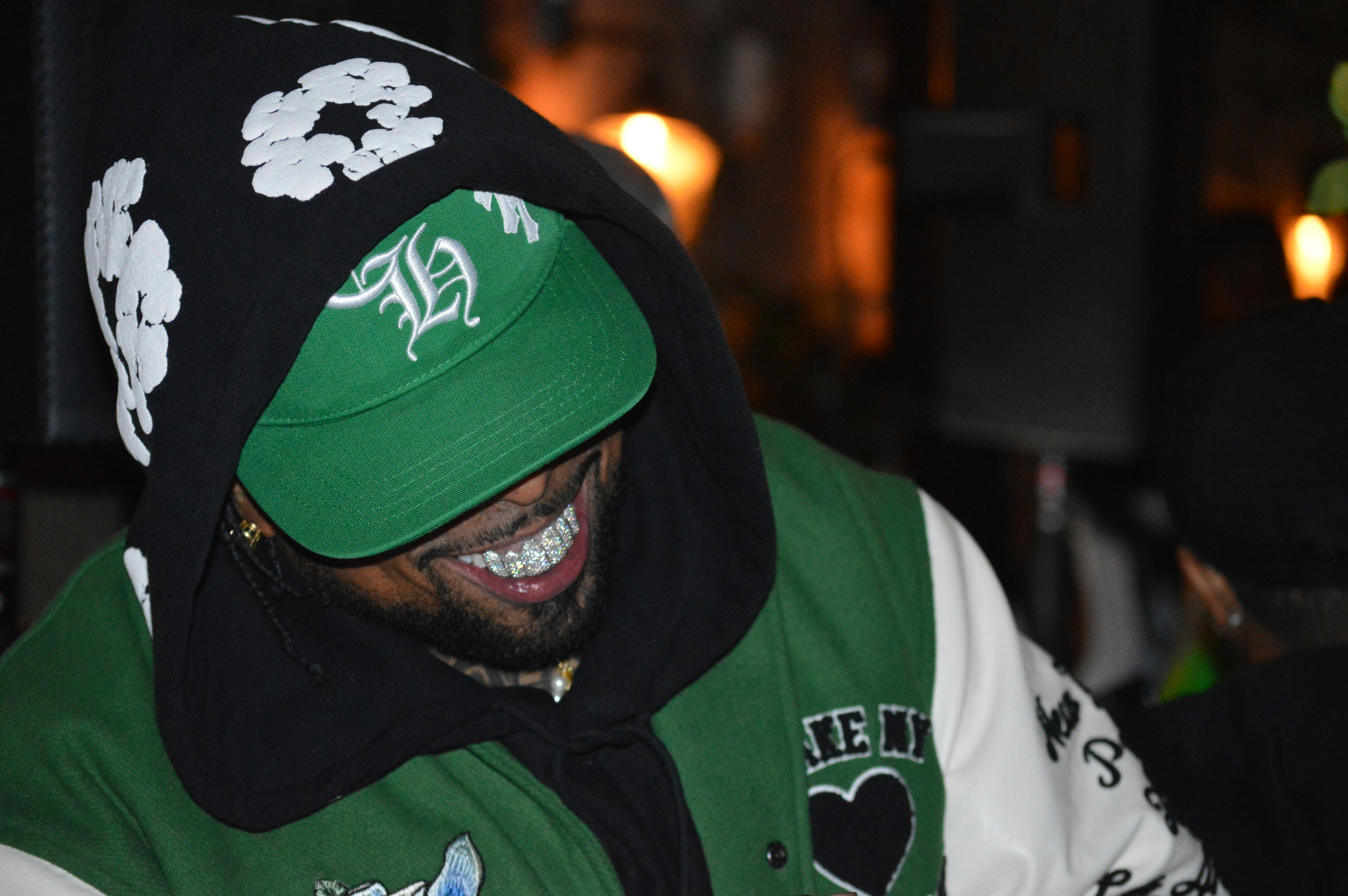 Green cap and hoodie, a candid grin in the nightlife