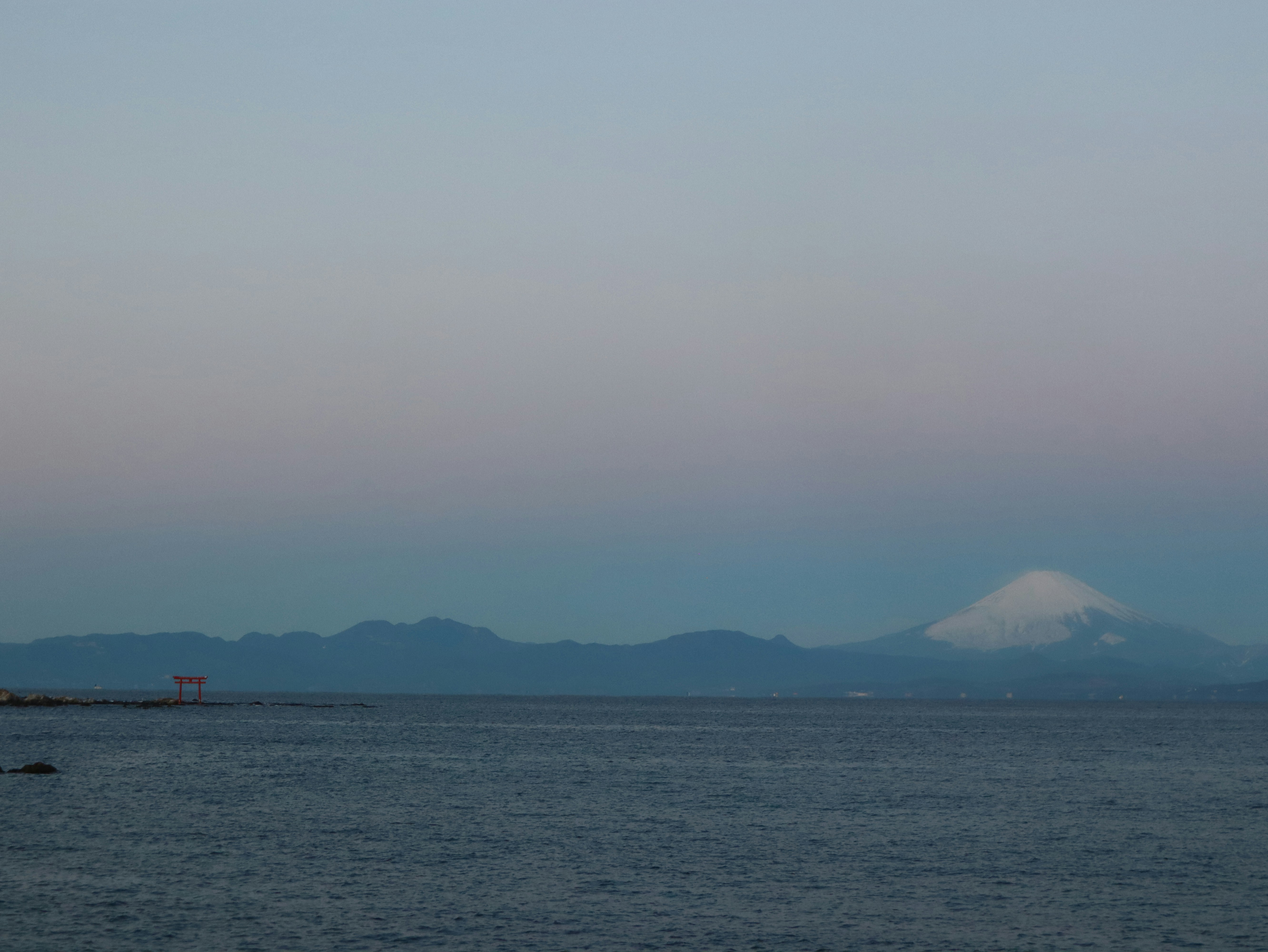 Distant Snow Peak Above a Serene Coastal Horizon