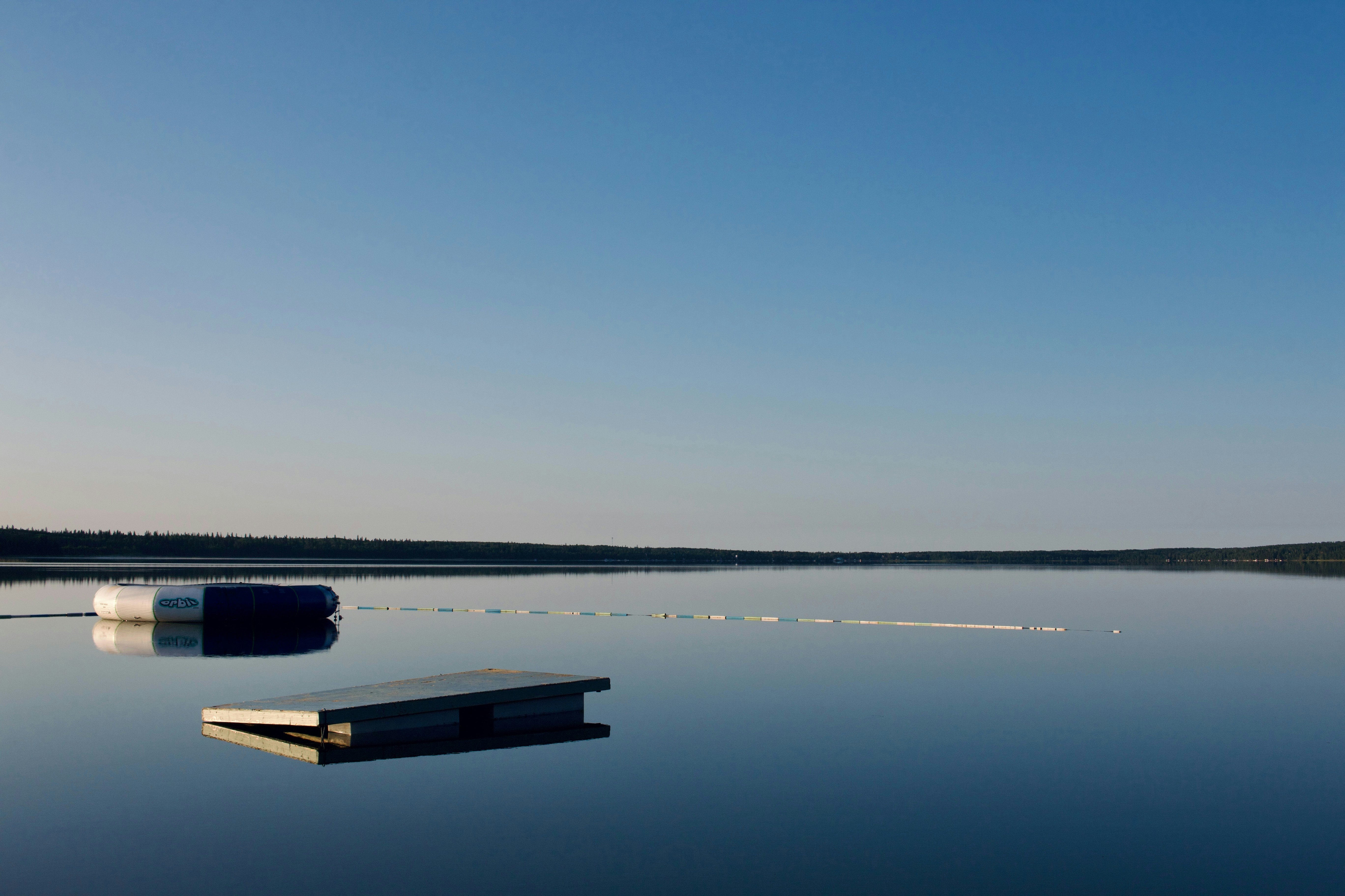 Floating Quiet: A Calm Dock Drifts Across a Mirrorlike Lake