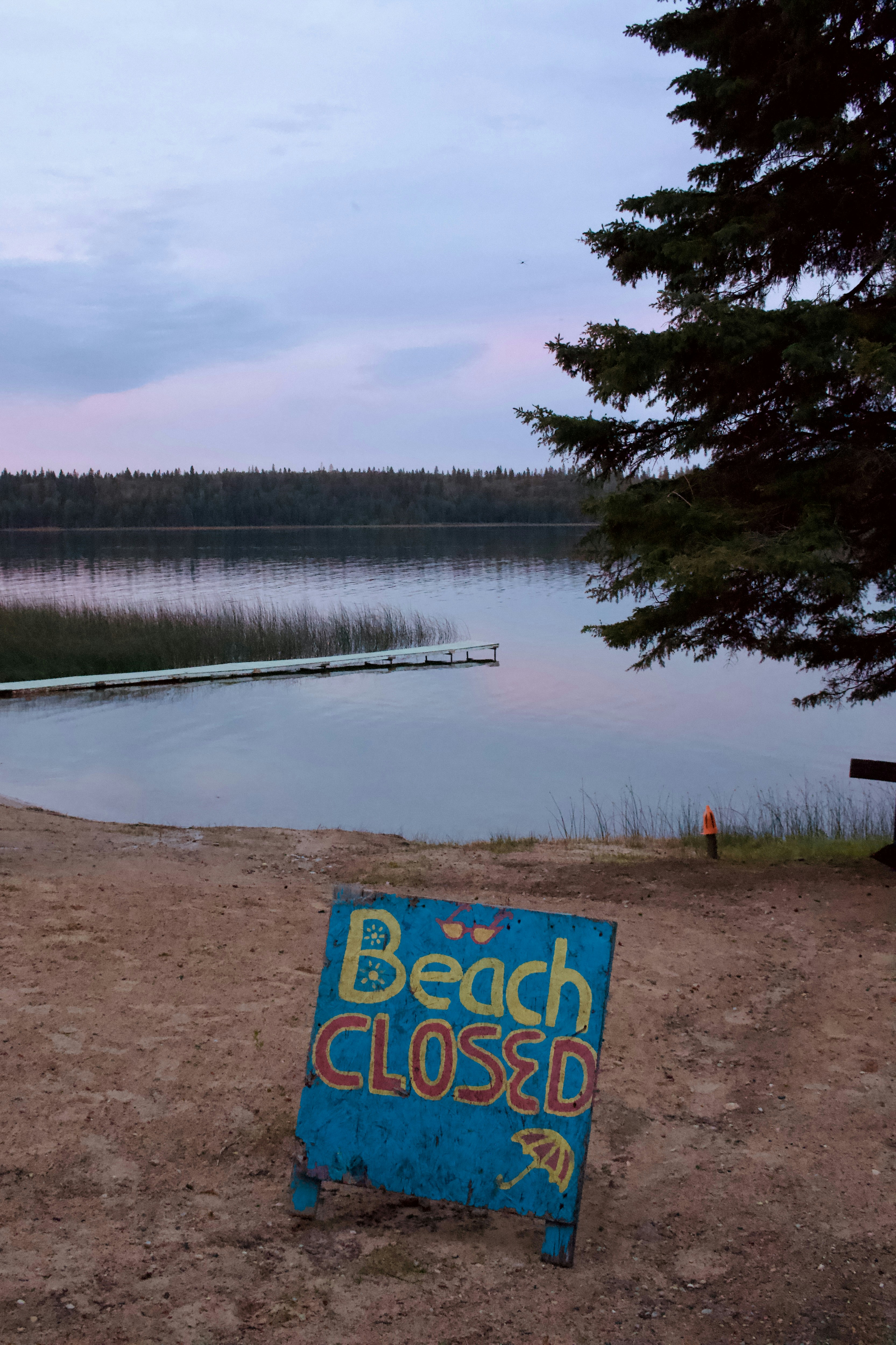 Beach Sign Sits at Dusk Above a Quiet Lake