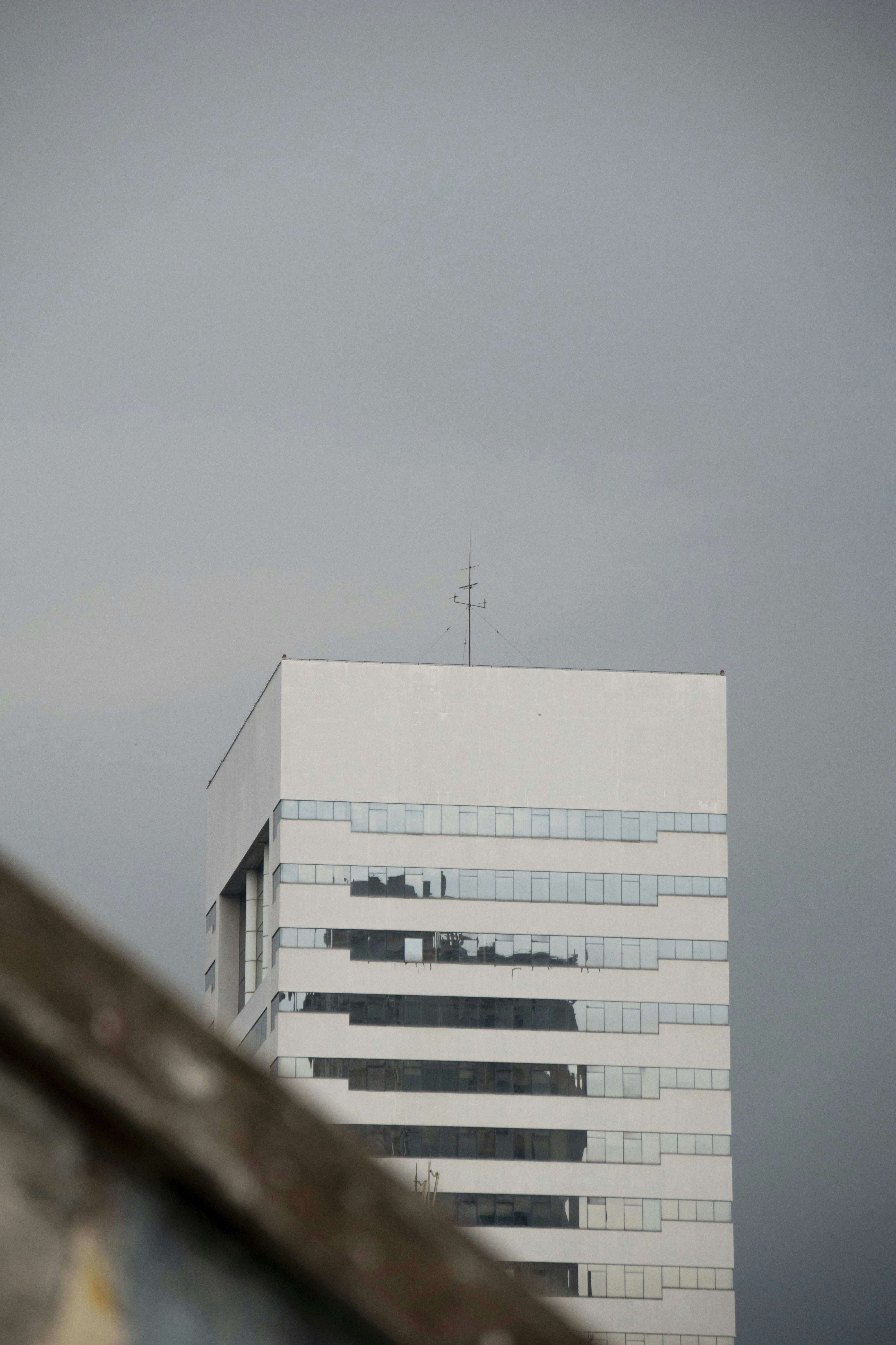 Sleek Corner: A High-Rloor Glass & Concrete Tower Peering Above a Sloped Foreground